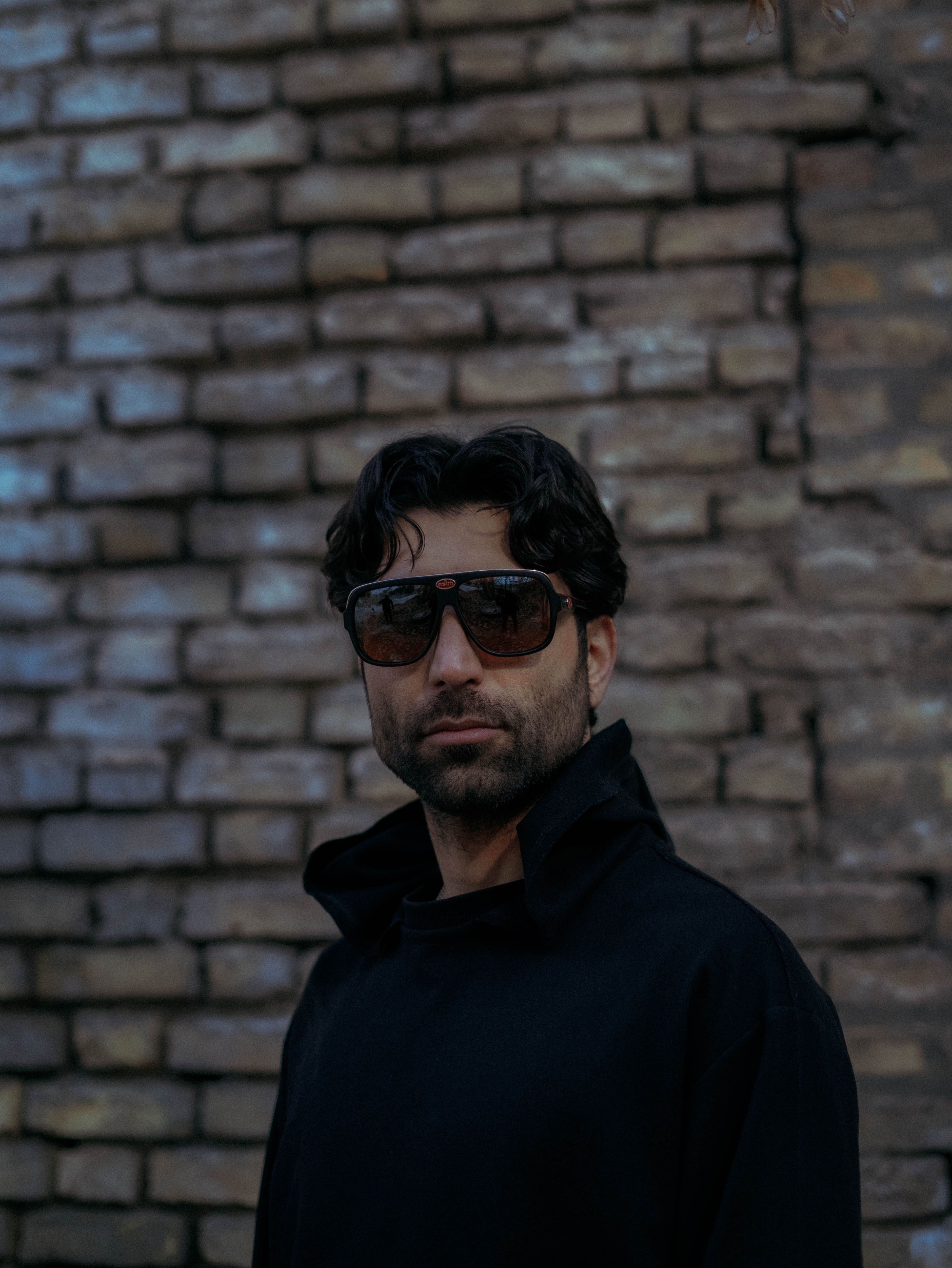 Man In Sunglasses Standing Against Brick Wall Free Stock Photo