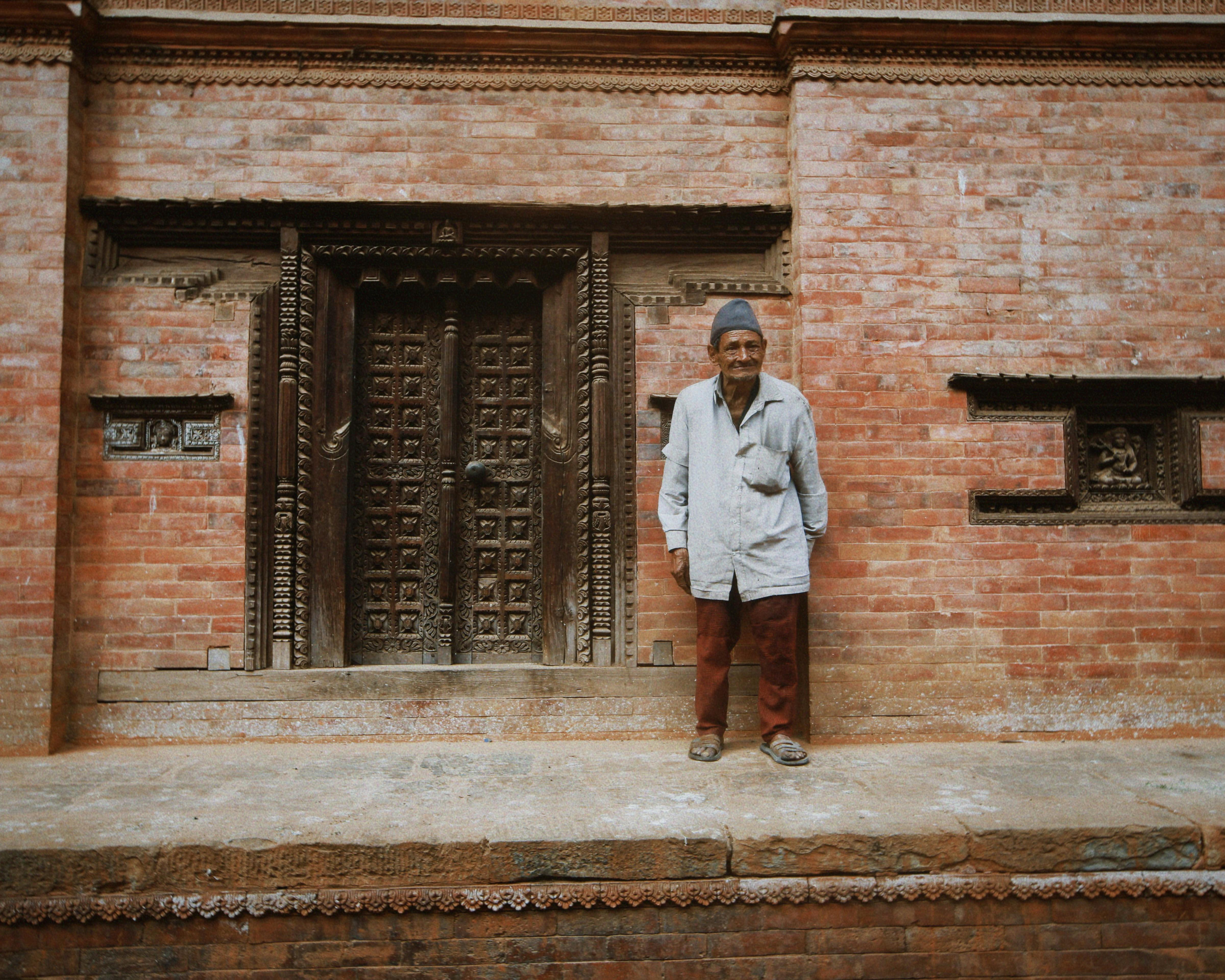 Elderly Man Standing by Traditional Brick Building · Free Stock Photo