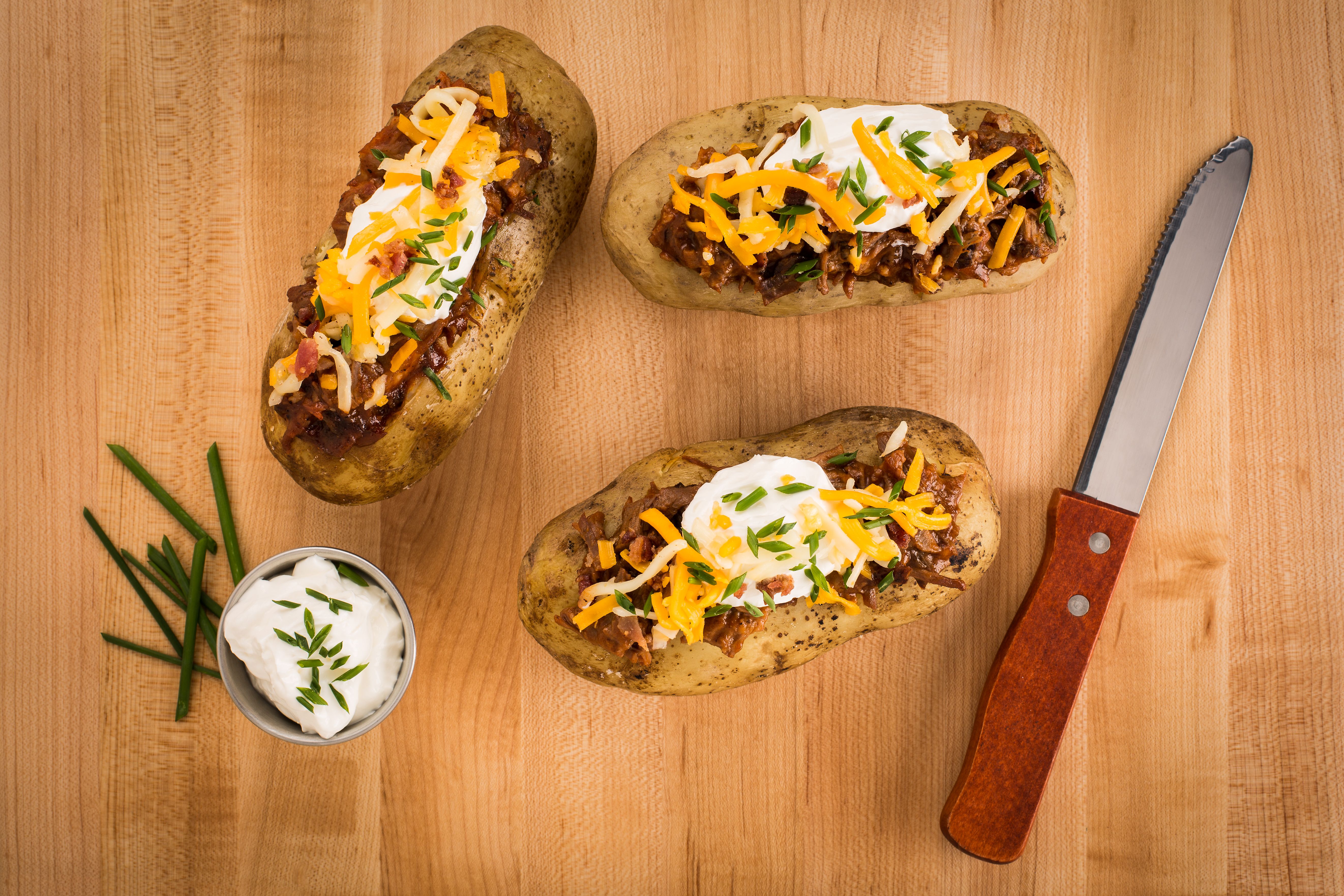 Delicious Loaded Baked Potatoes on Wood Surface · Free Stock Photo