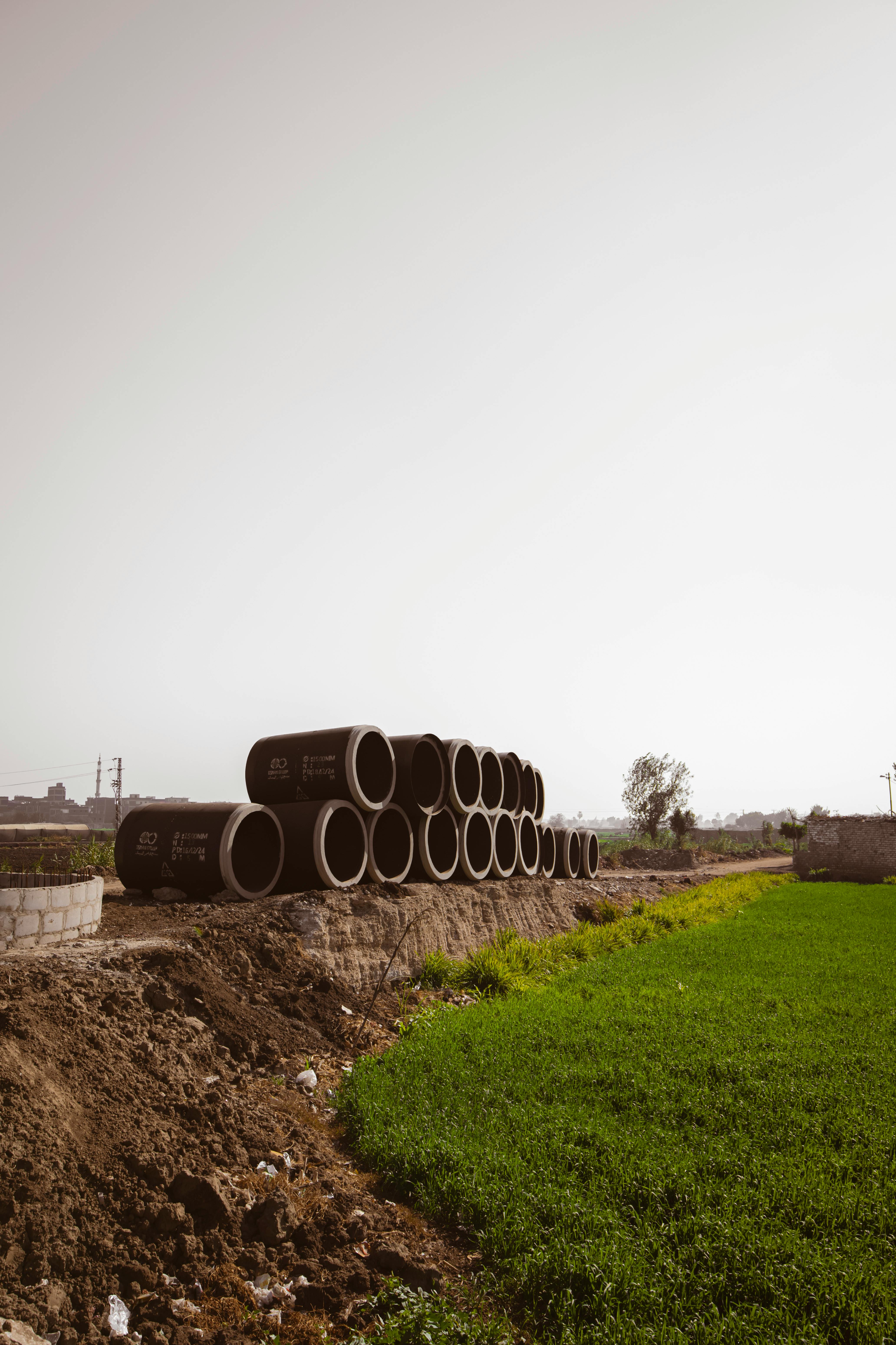 Stack of Large Concrete Pipes in Rural Field · Free Stock Photo