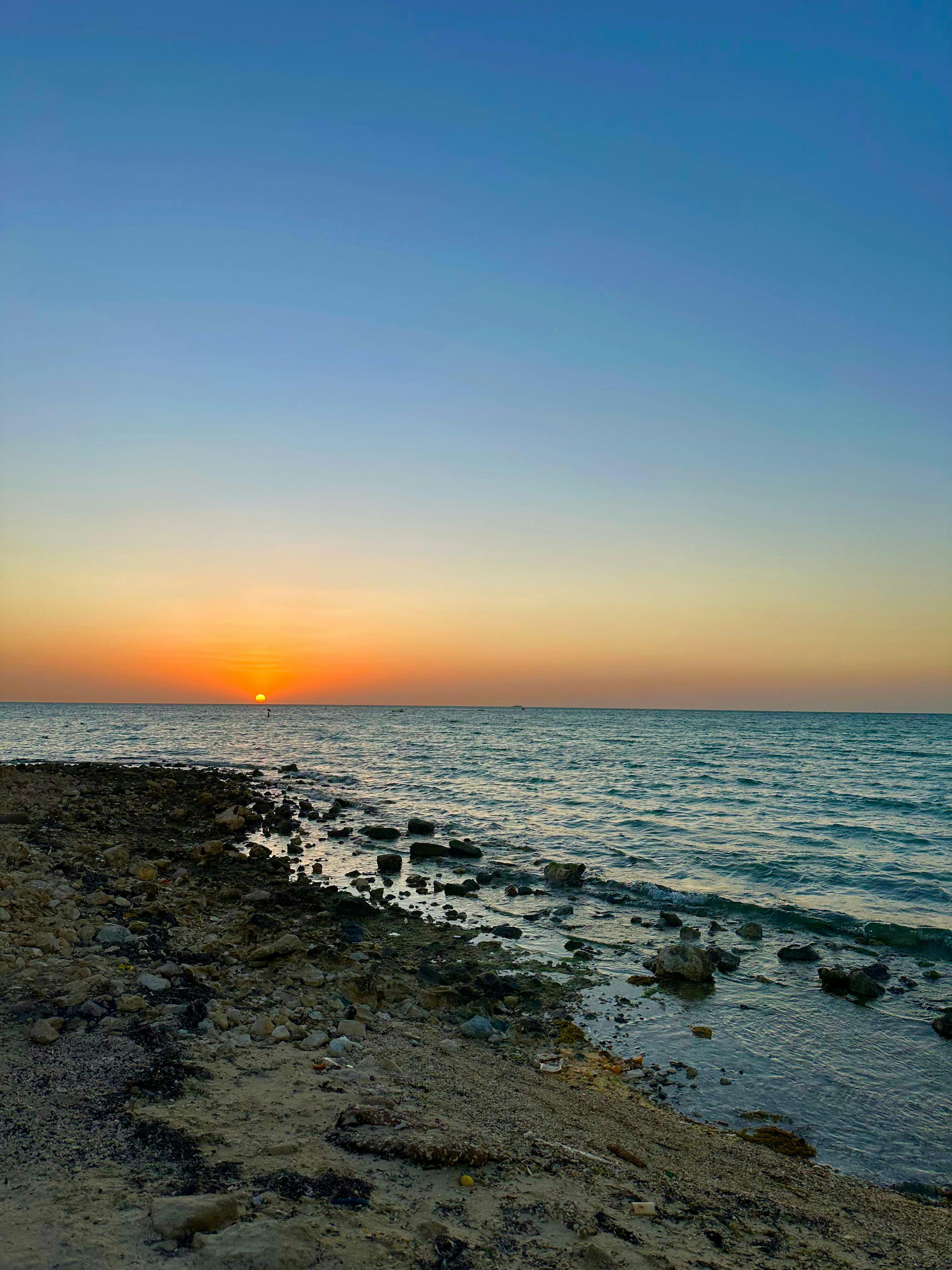 Serene Ocean Sunset with Rocky Shoreline · Free Stock Photo