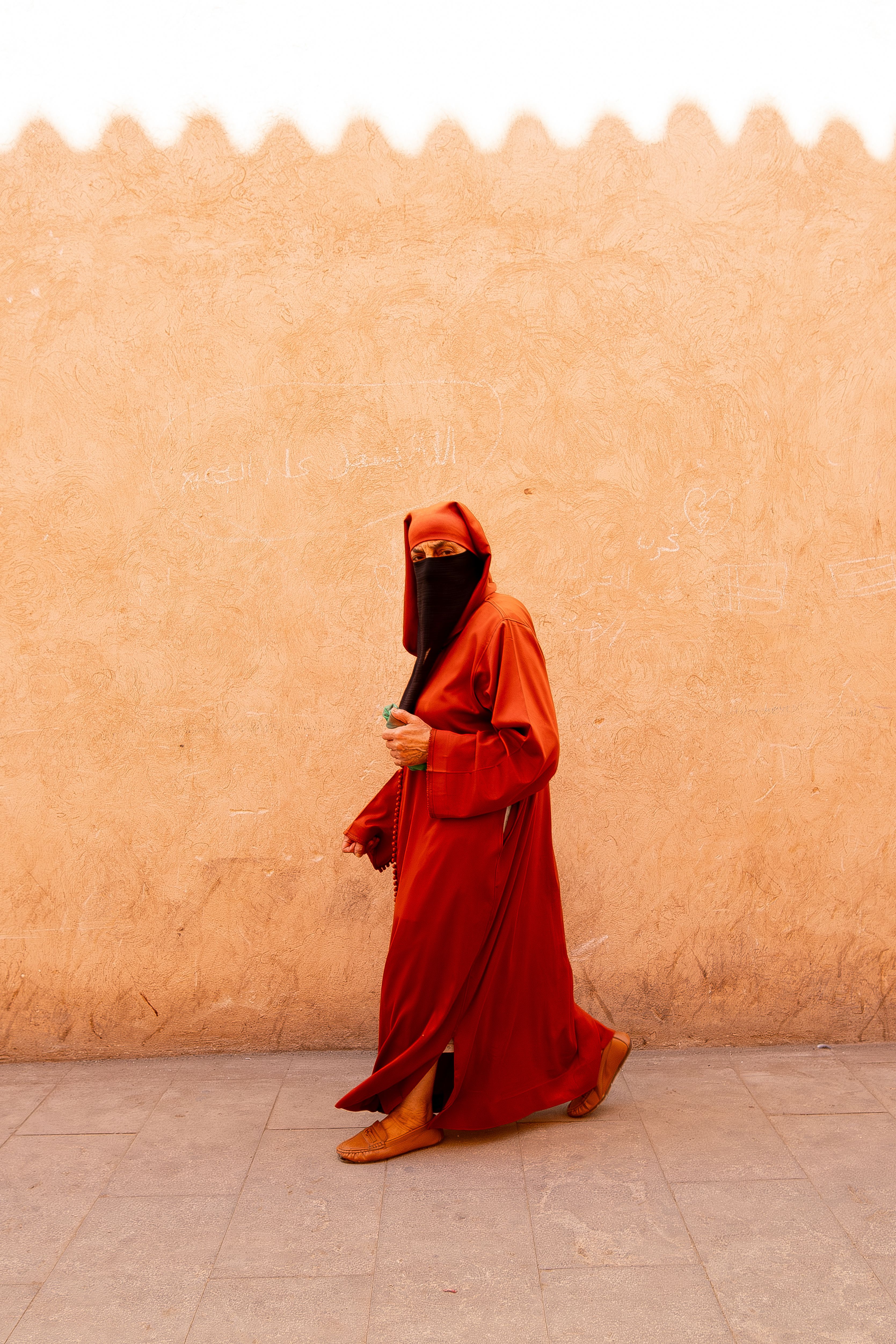 Person in Traditional Robe Walking by Textured Wall · Free Stock Photo