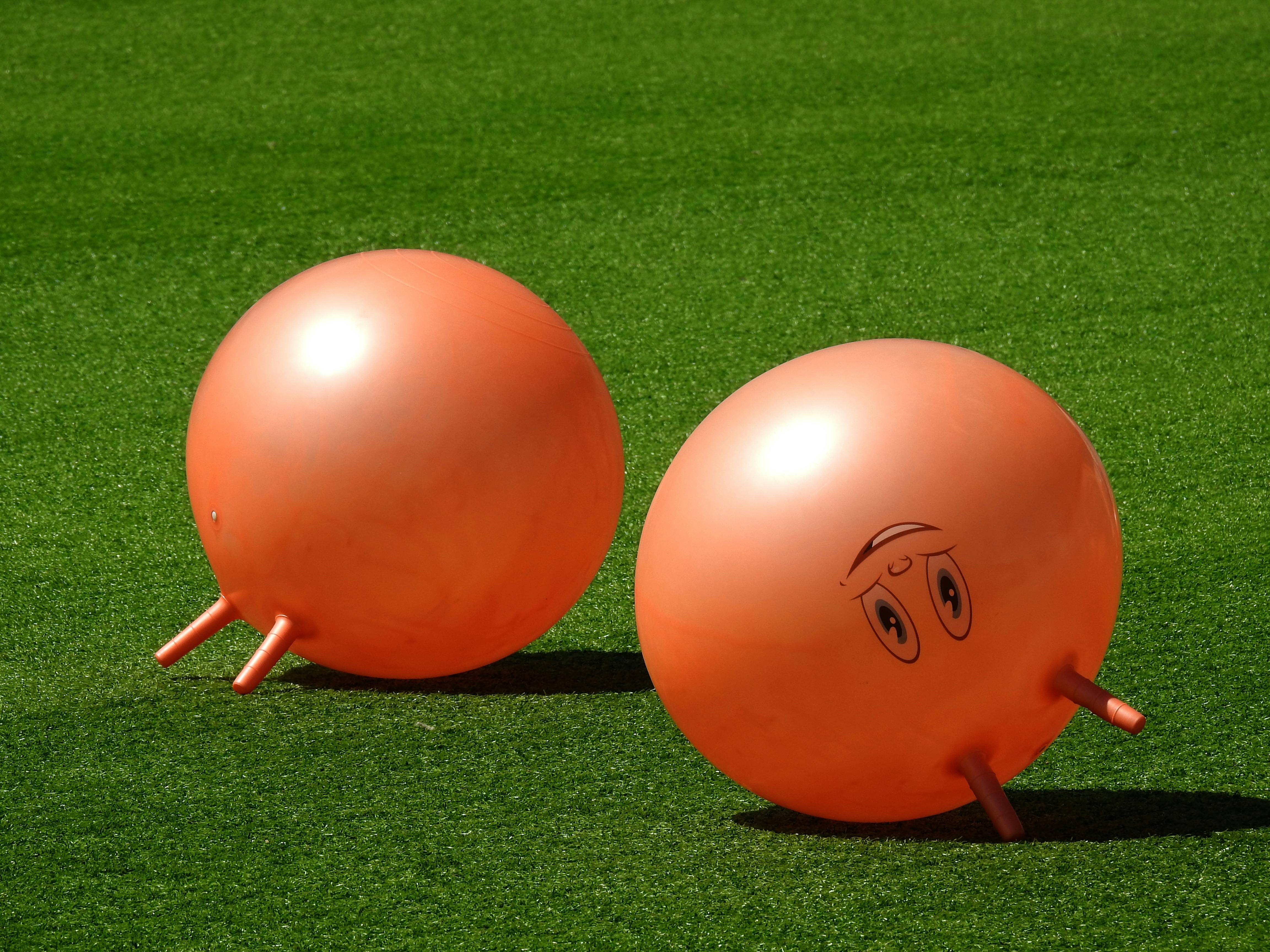 Playful Orange Hopper Balls on Green Lawn · Free Stock Photo