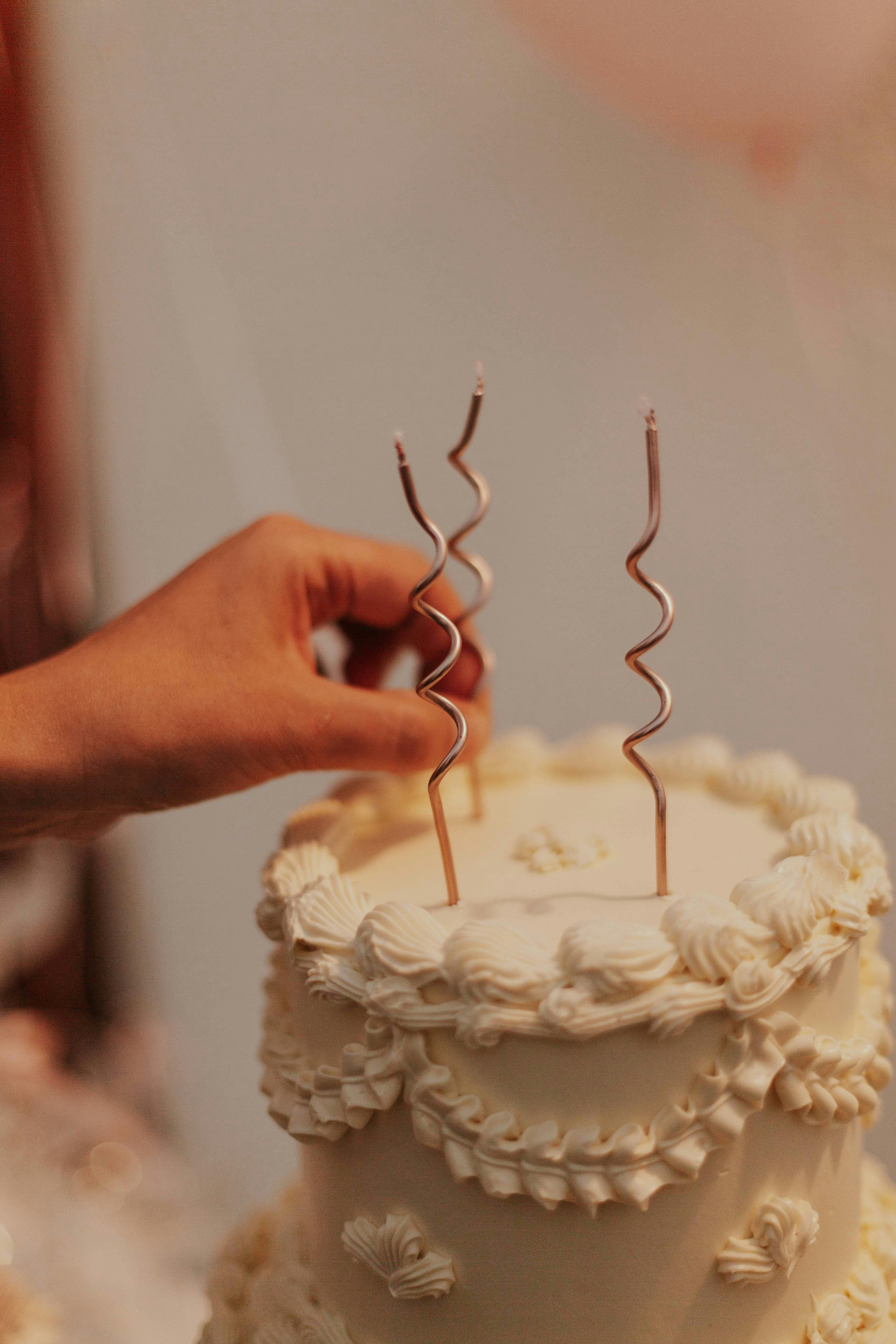 Hand Placing Twisted Candles on Elegant Cake · Free Stock Photo