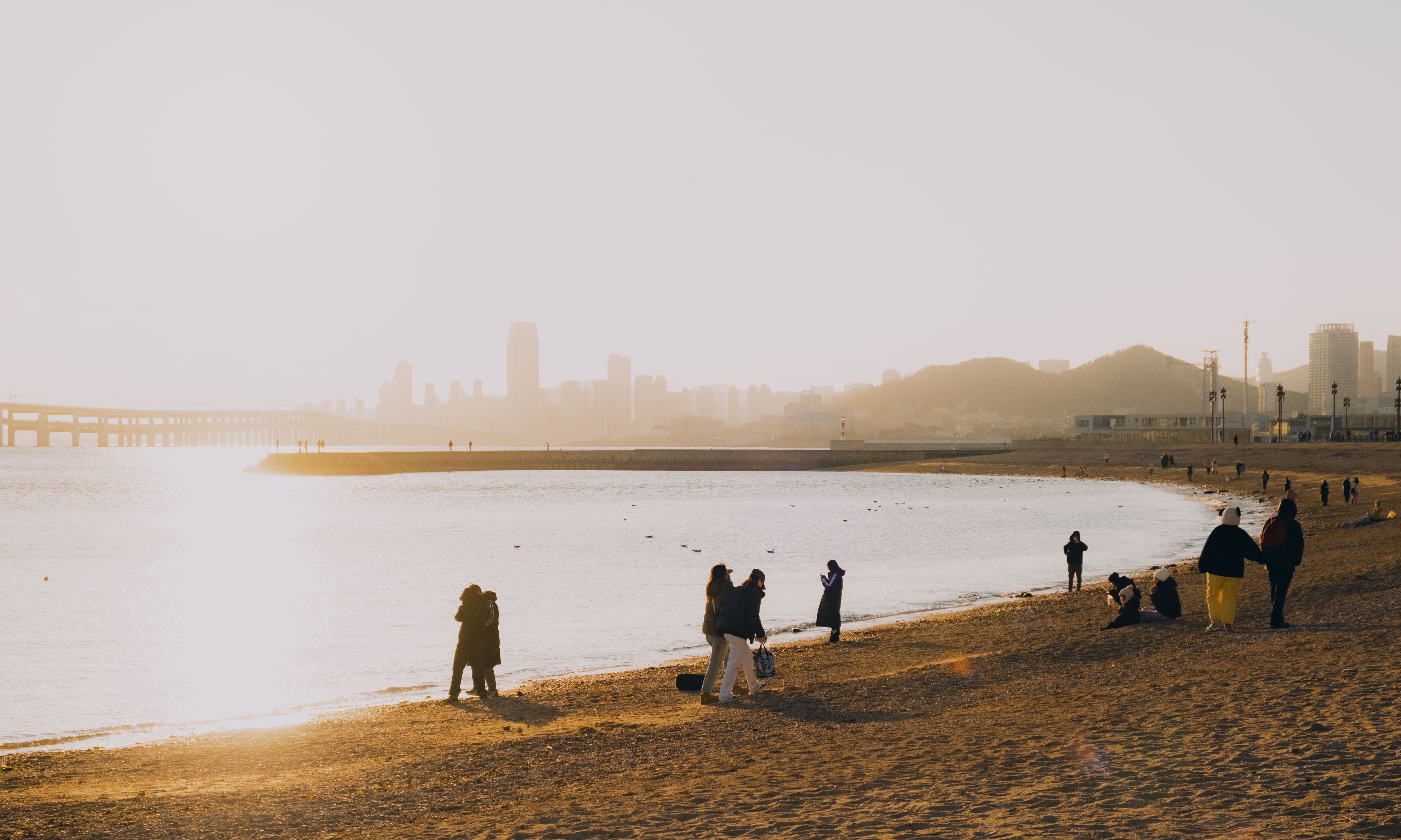 Sunlit City Beach with People Strolling · Free Stock Photo