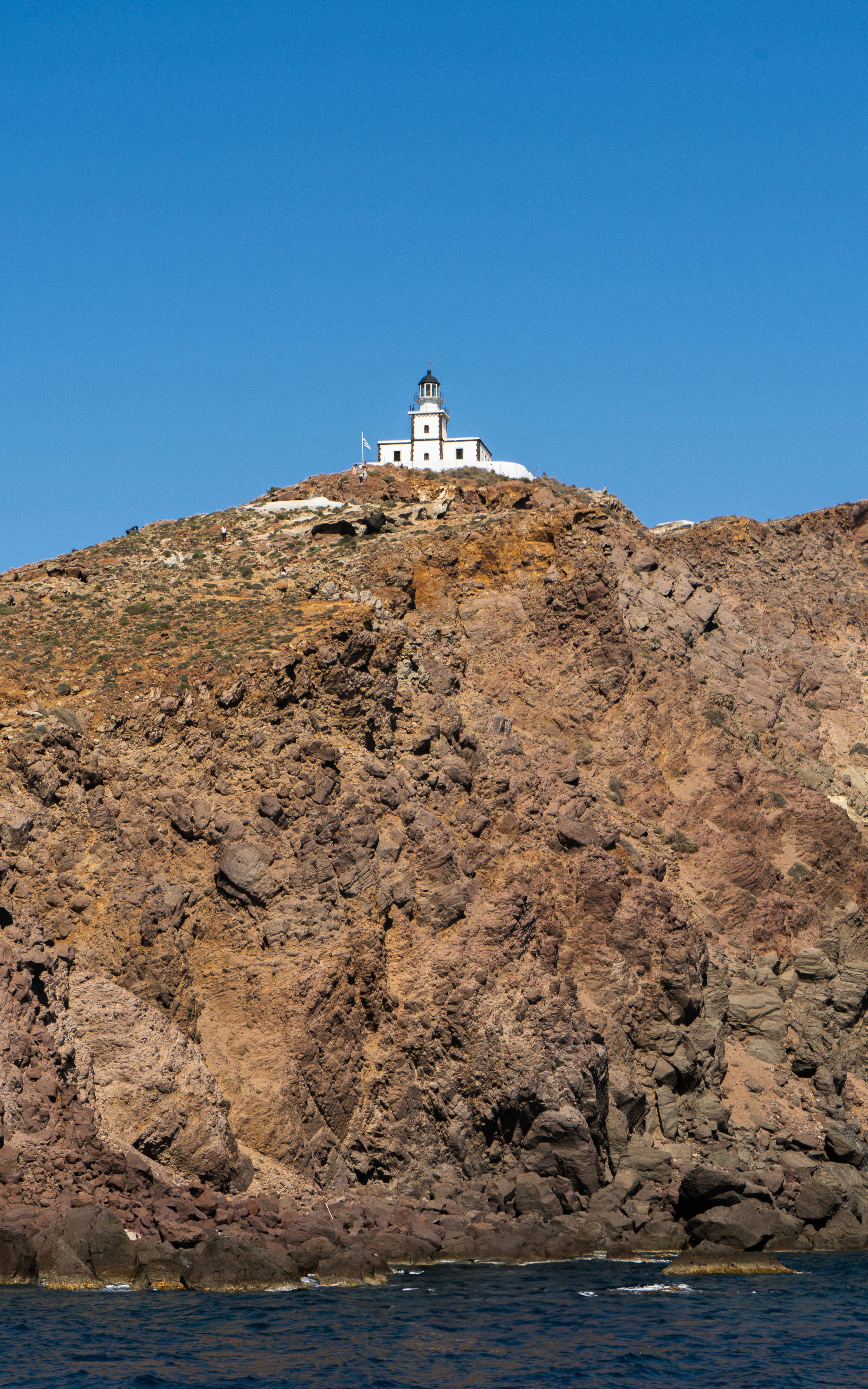 Santorini Lighthouse on Rugged Cliffside · Free Stock Photo
