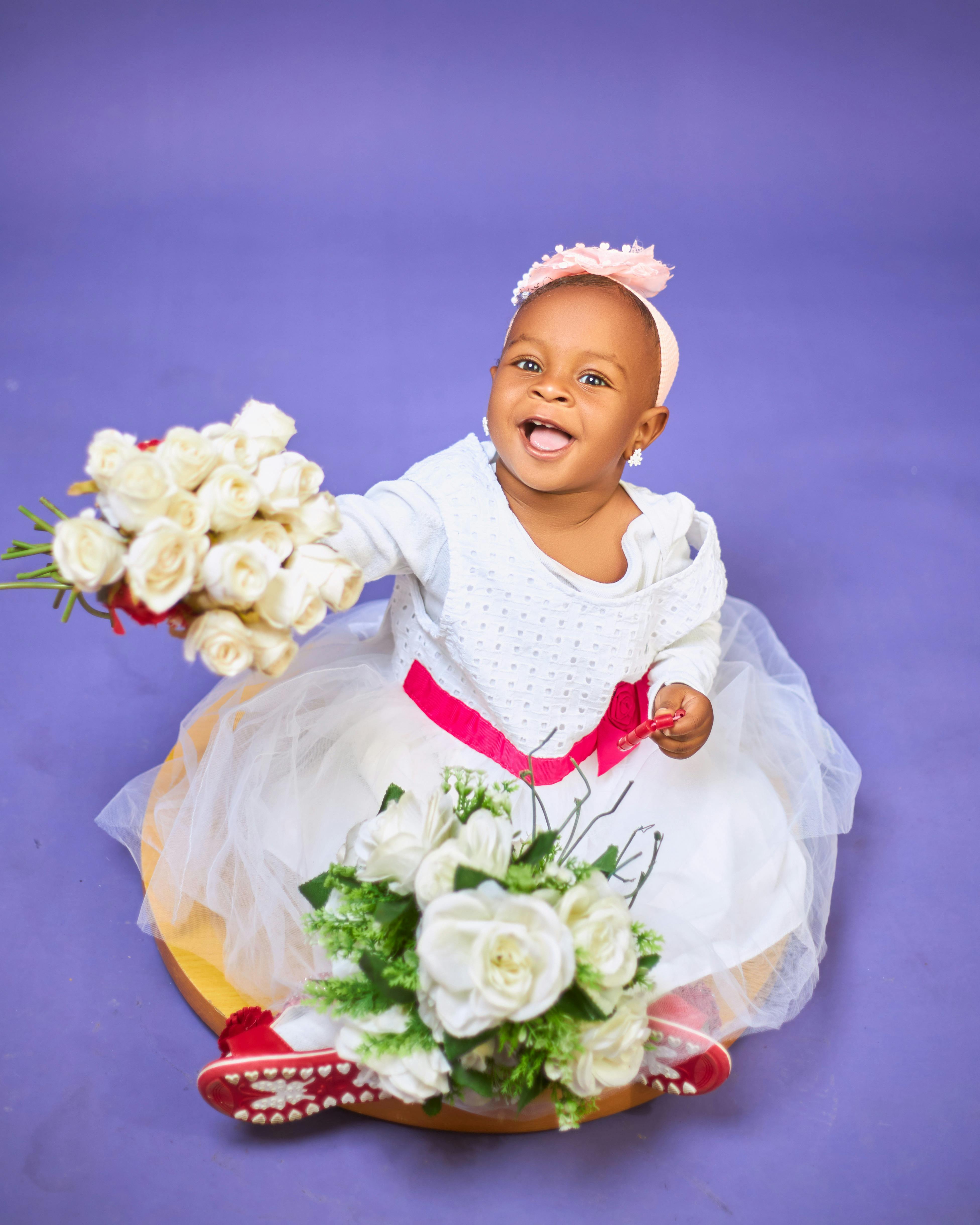 Joyful Baby with Roses Against Purple Backdrop · Free Stock Photo