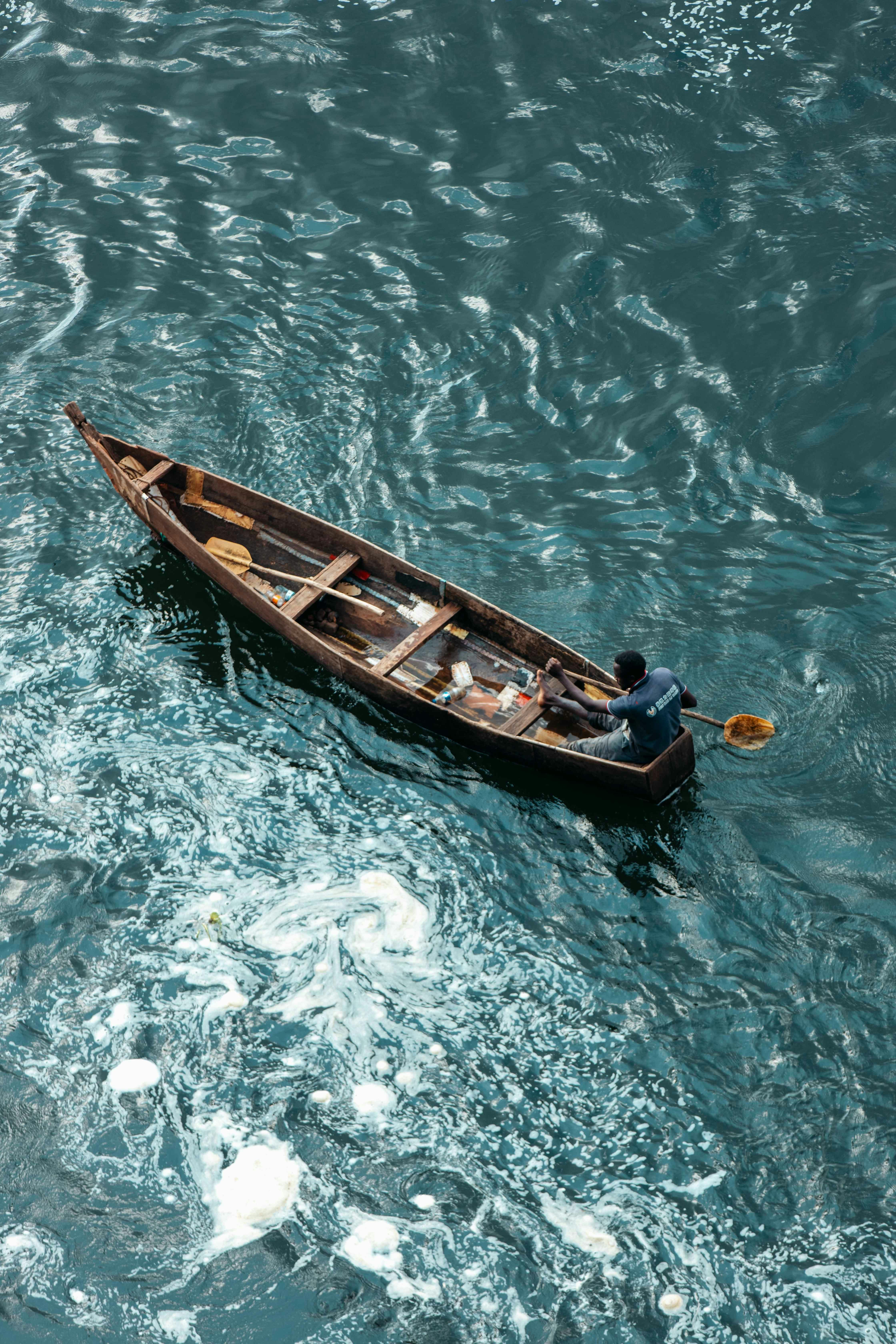 Aerial View of Man Rowing Wooden Boat in Blue Water · Free Stock Photo