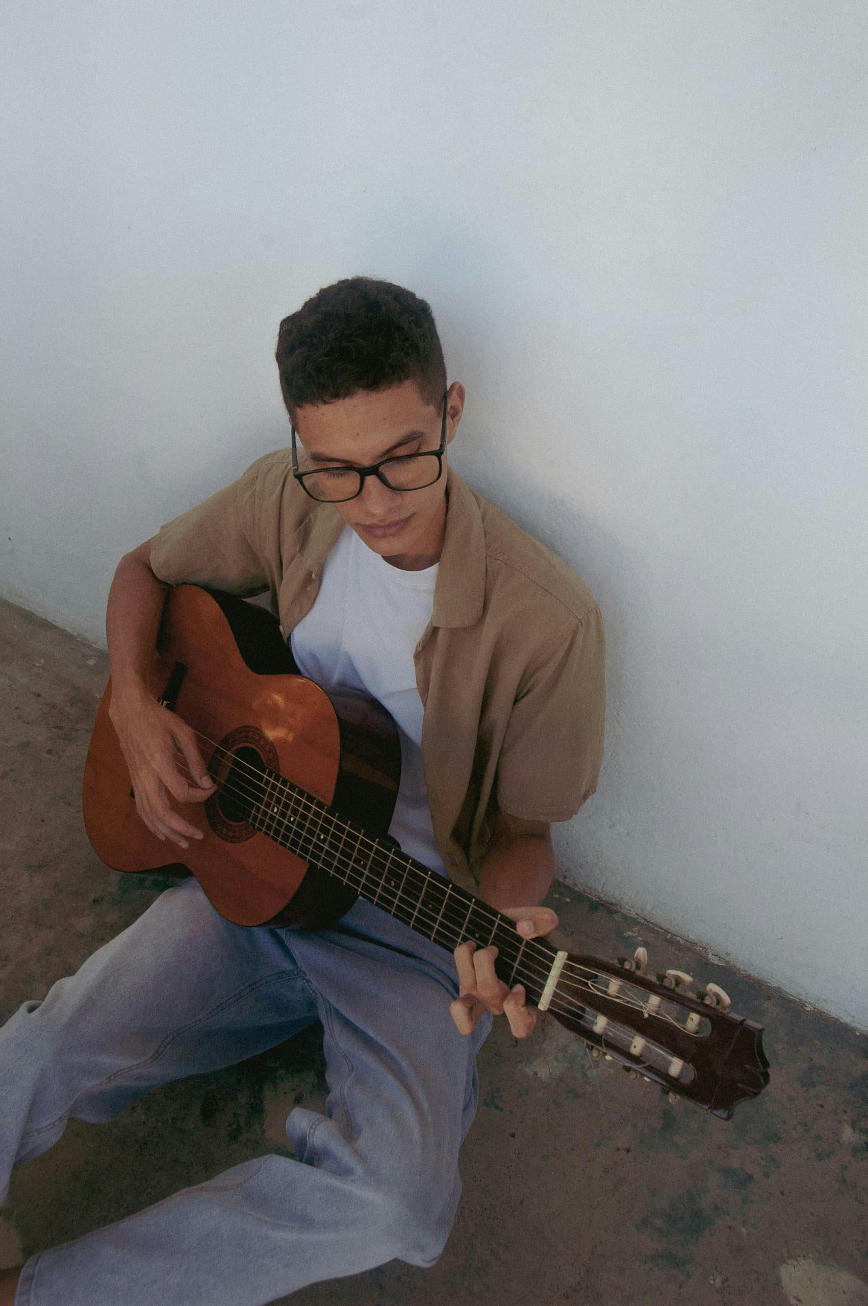 Young Man Playing Acoustic Guitar in Relaxed Setting · Free Stock Photo