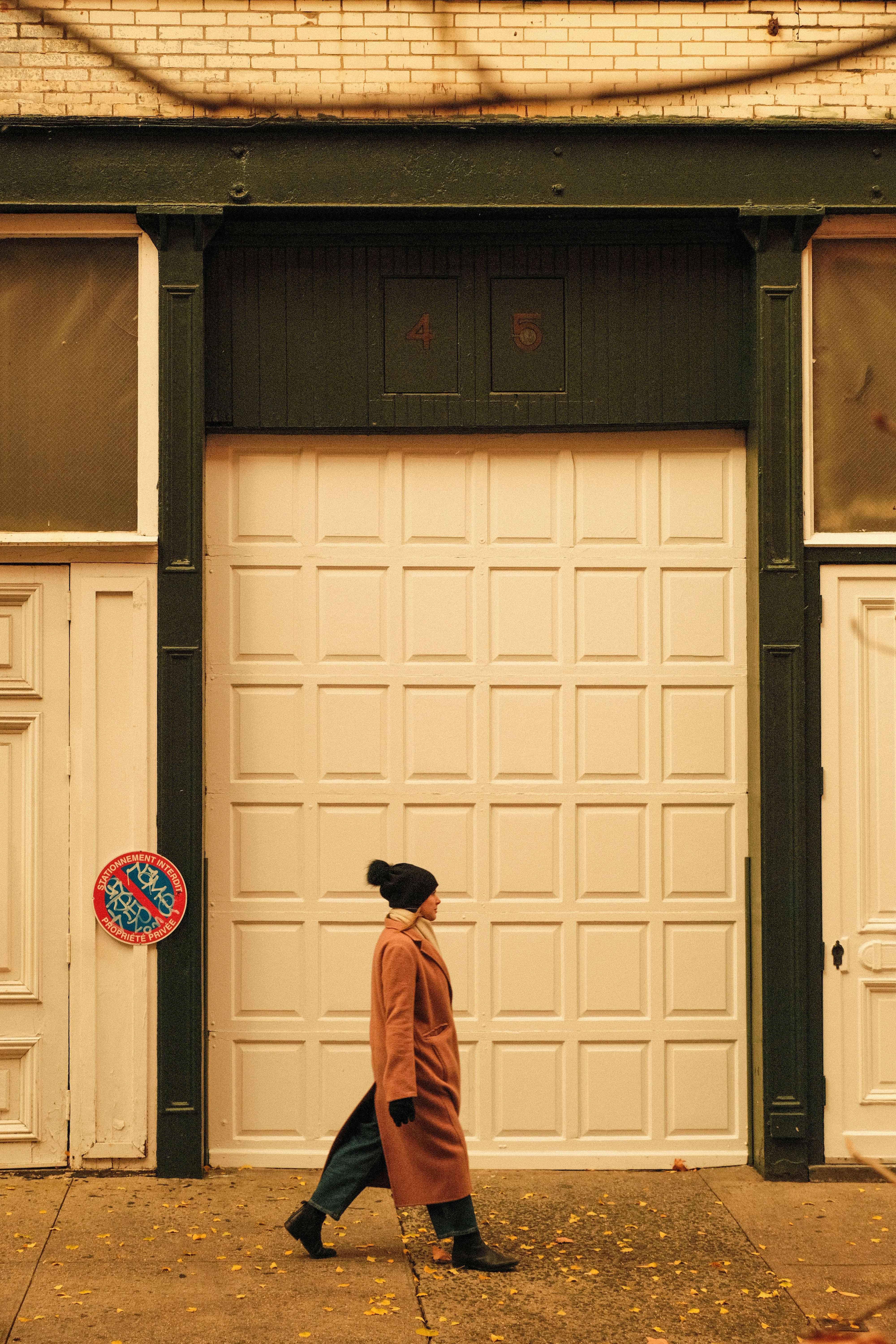 Woman Walking Past Vintage Garage Door Outdoors · Free Stock Photo