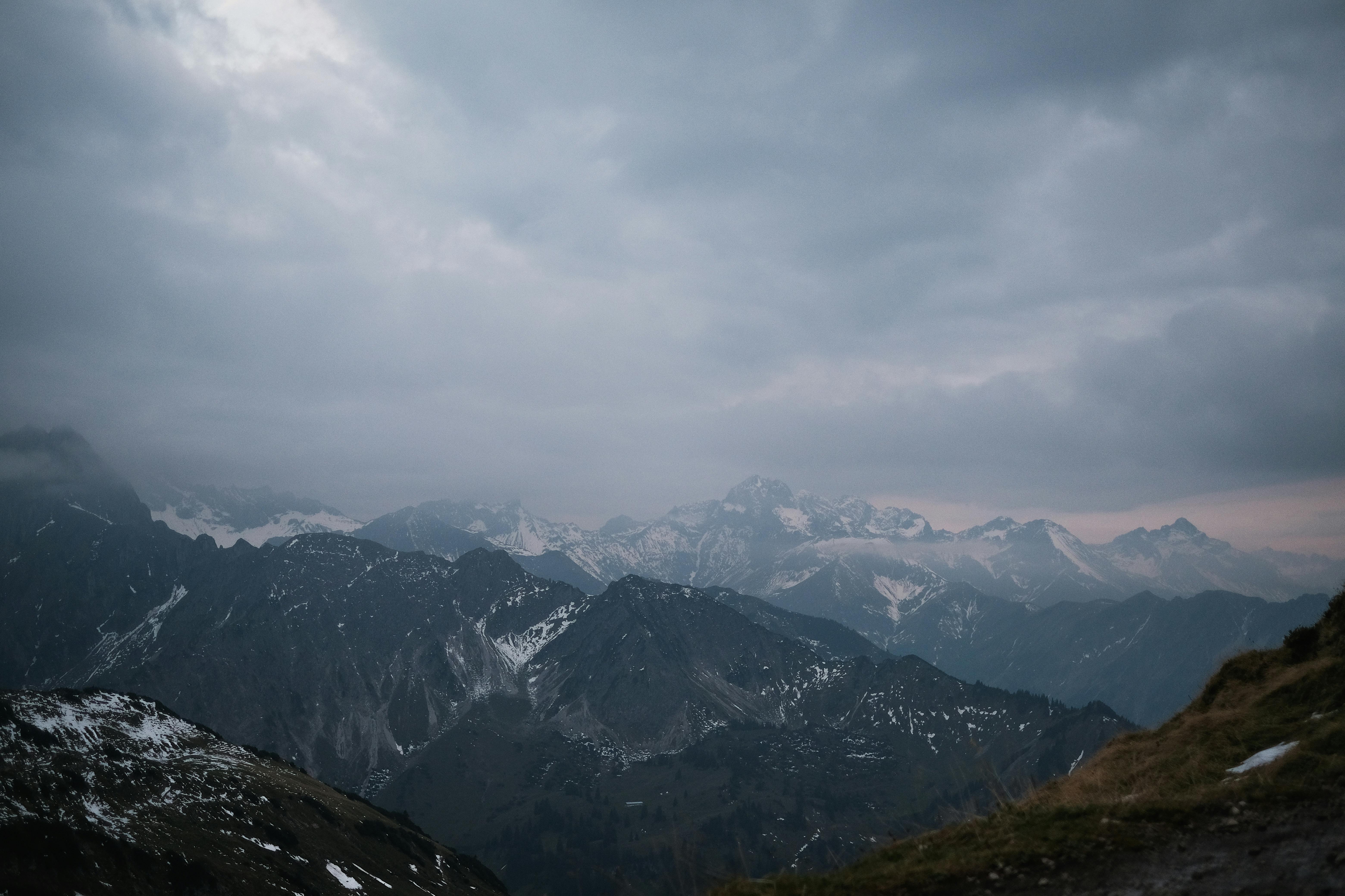 Dramatic Snow-Capped Mountain Range Under Cloudy Sky · Free Stock Photo