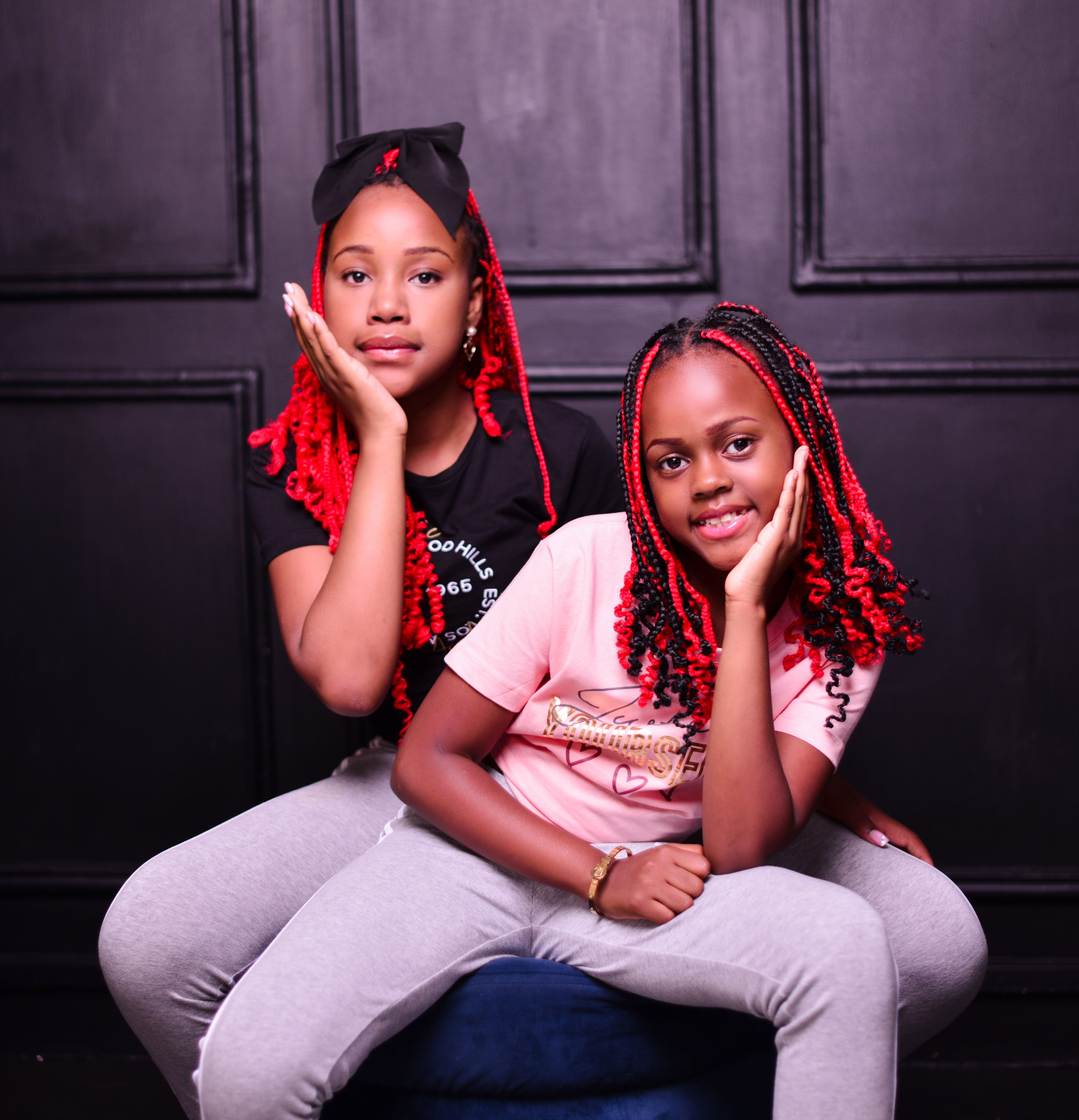 Joyful Sisters Posing Indoors with Red Braids · Free Stock Photo