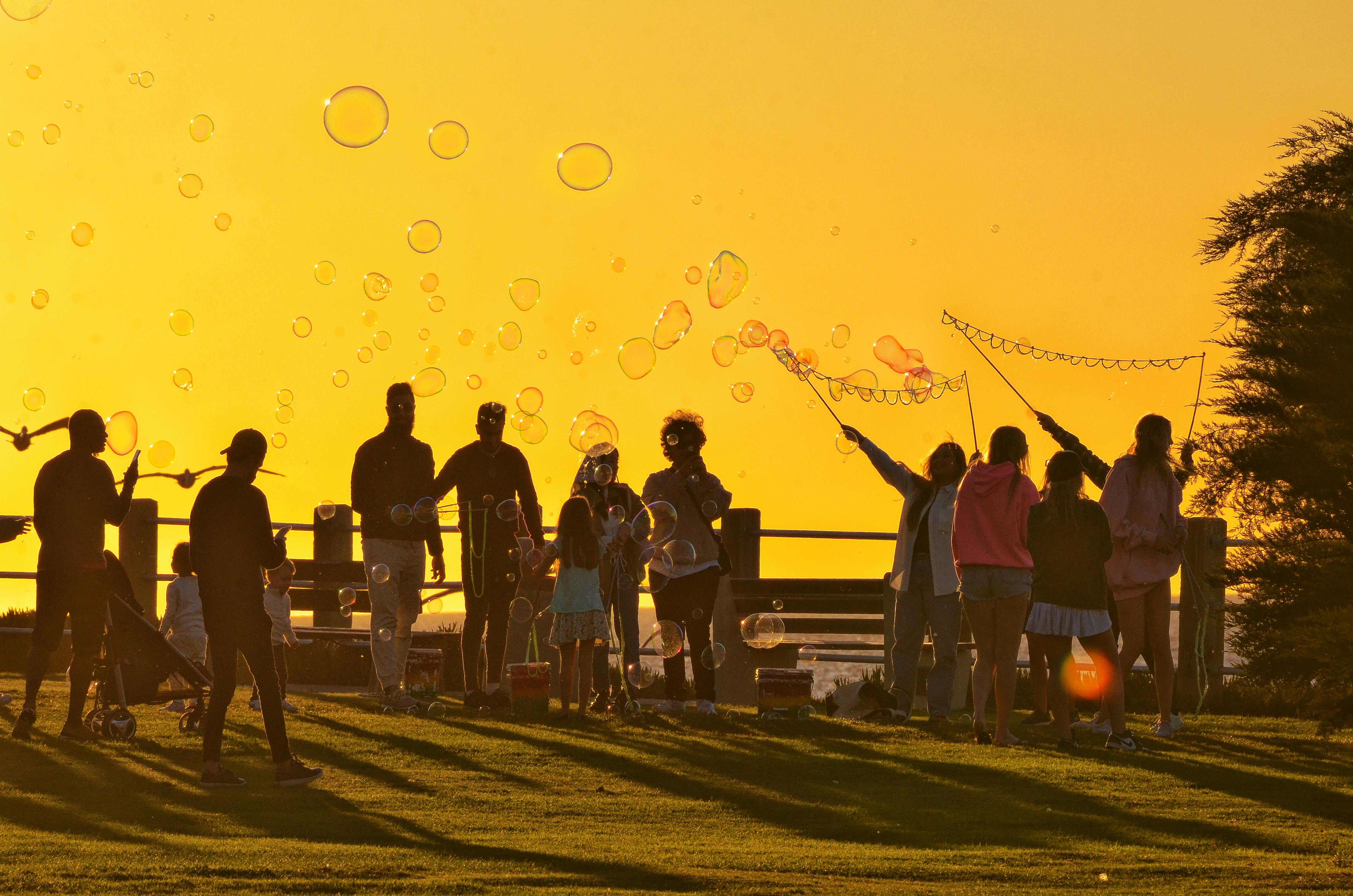 People Enjoying Bubble Fun at Sunset in San Diego Park · Free Stock Photo