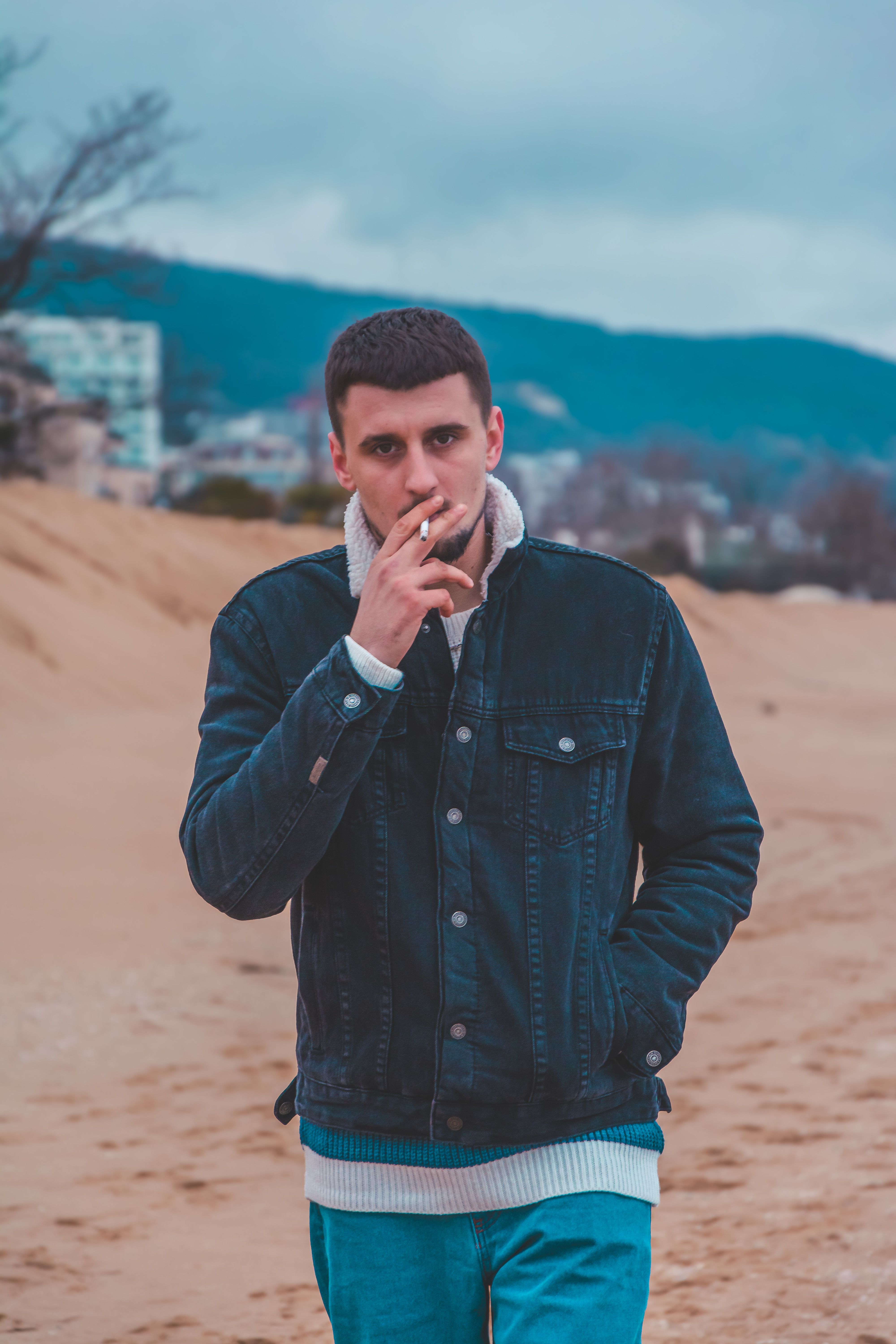 Man Smoking on Beach in Denim Jacket · Free Stock Photo