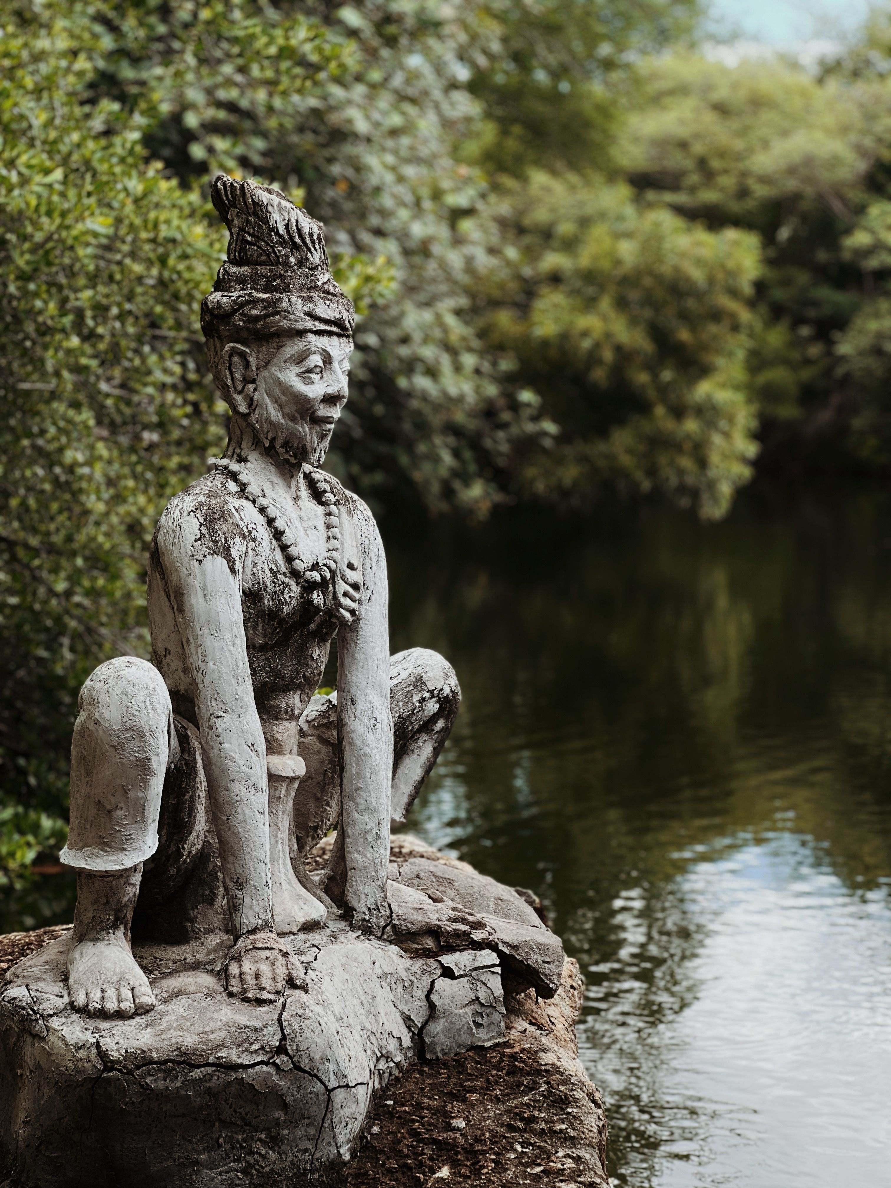 Ancient Stone Statue by a Tranquil River · Free Stock Photo