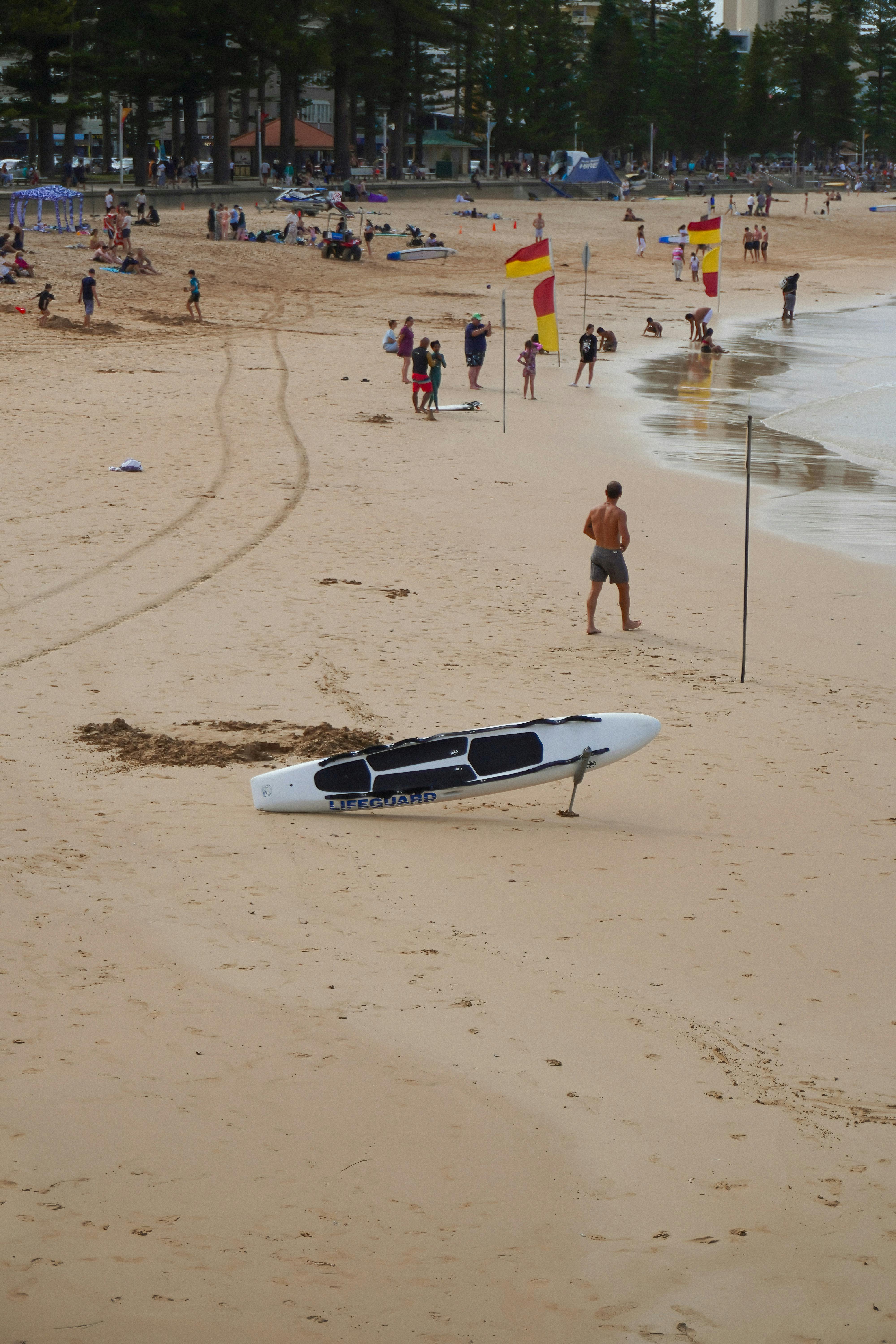 Busy Beach Scene with Lifeguards and Canoe · Free Stock Photo