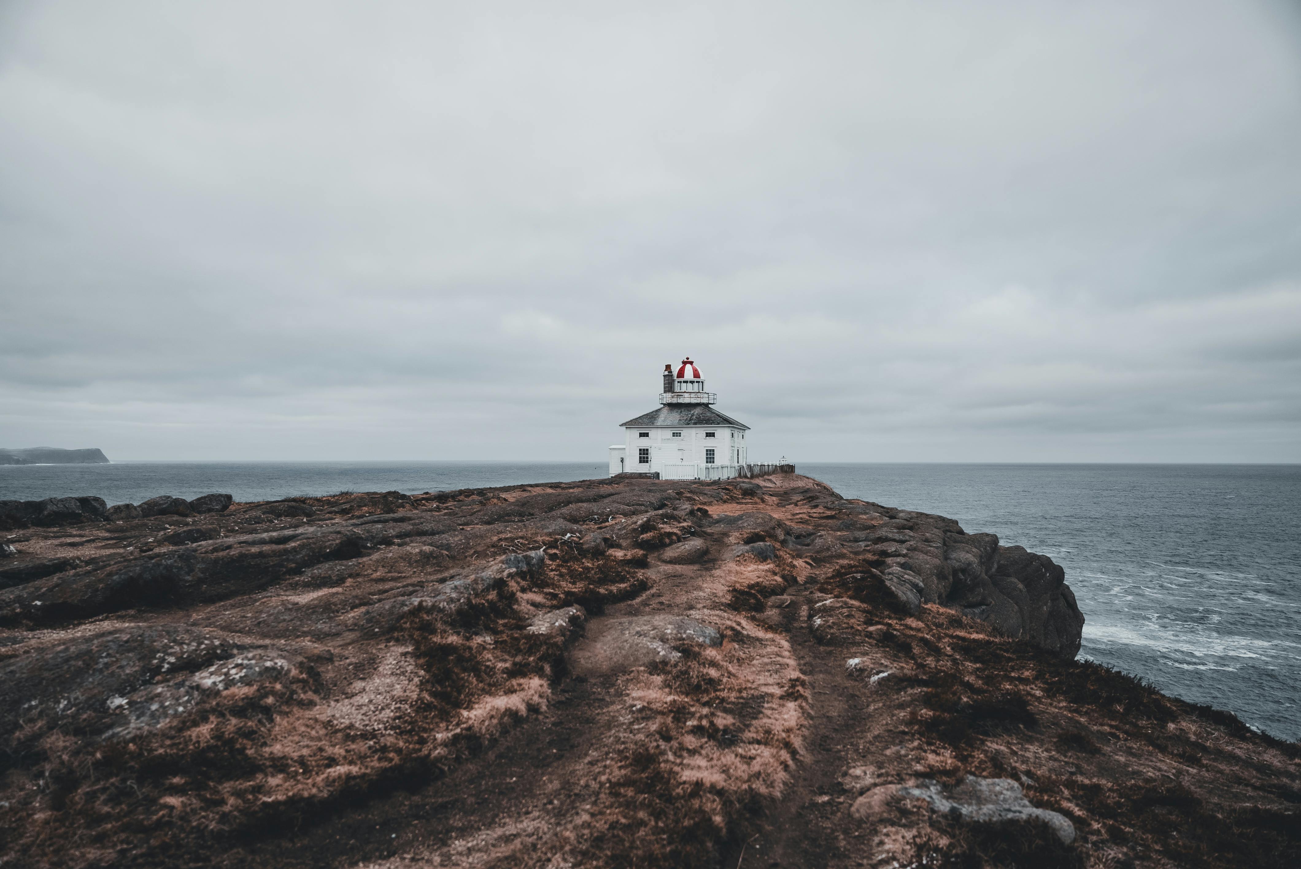 Dramatic Lighthouse on Rocky Coastline · Free Stock Photo