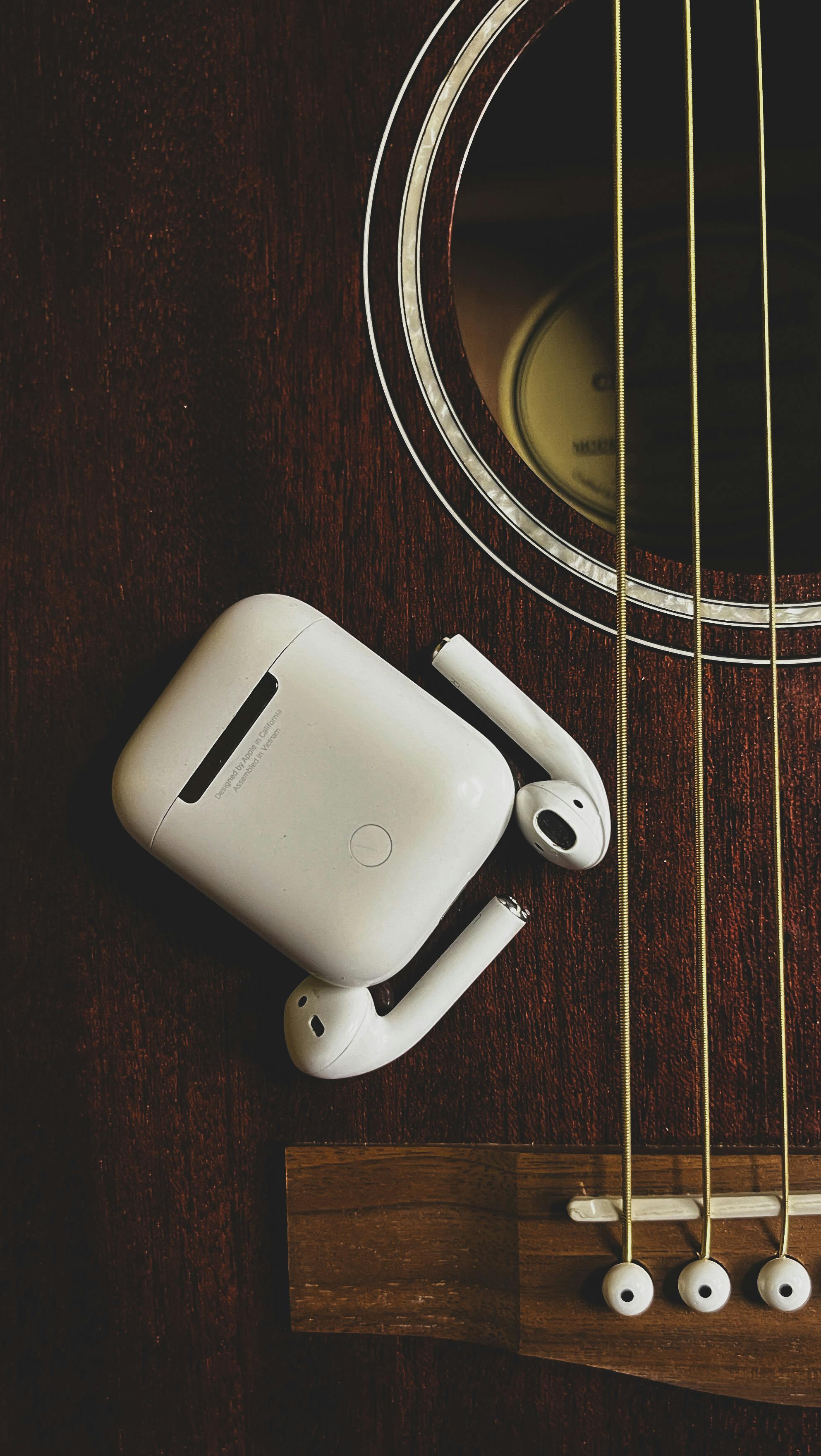 Acoustic Guitar with Wireless Earbuds on Strings · Free Stock Photo