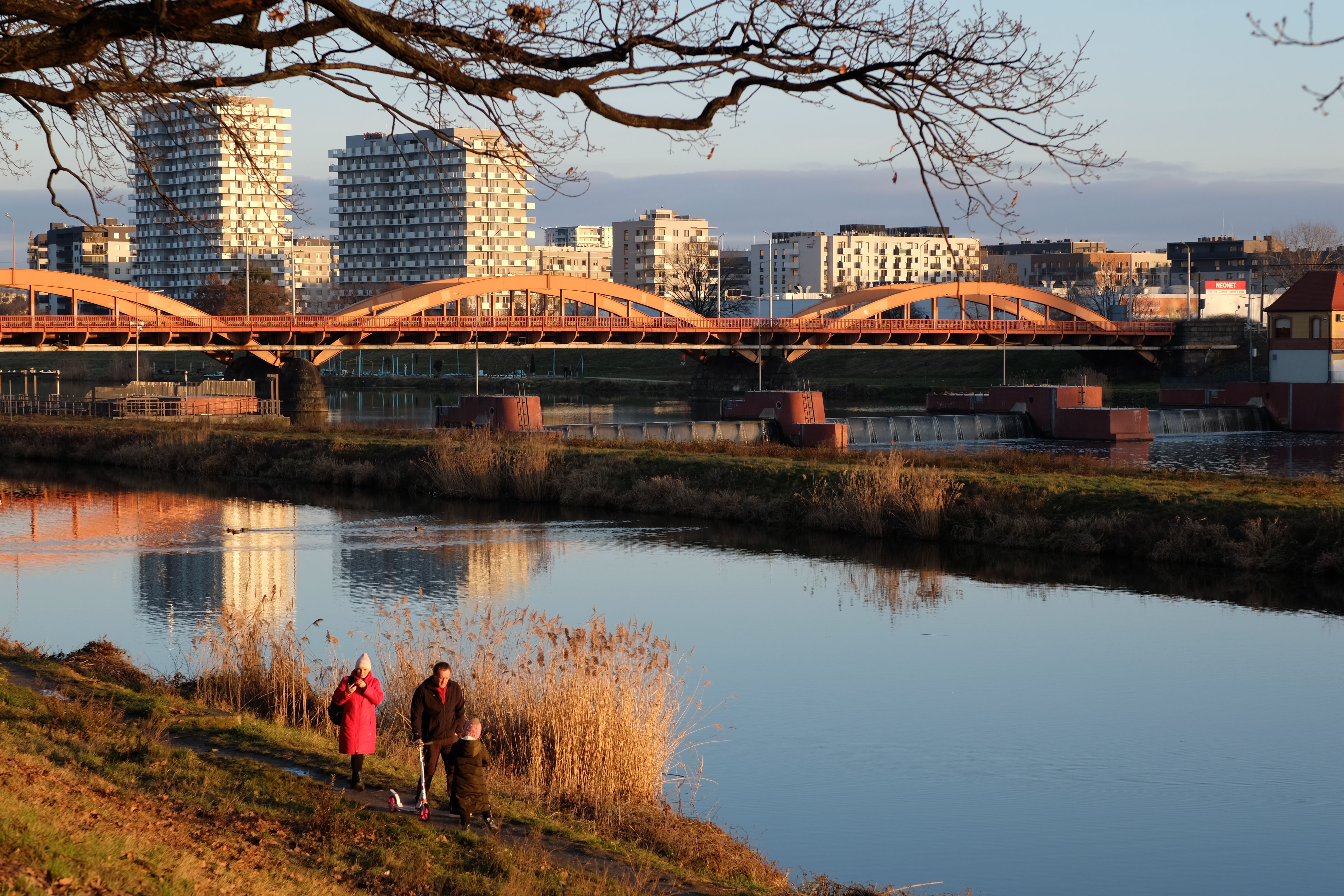 Scenic Urban River View with Arched Bridge and Strollers · Free Stock Photo