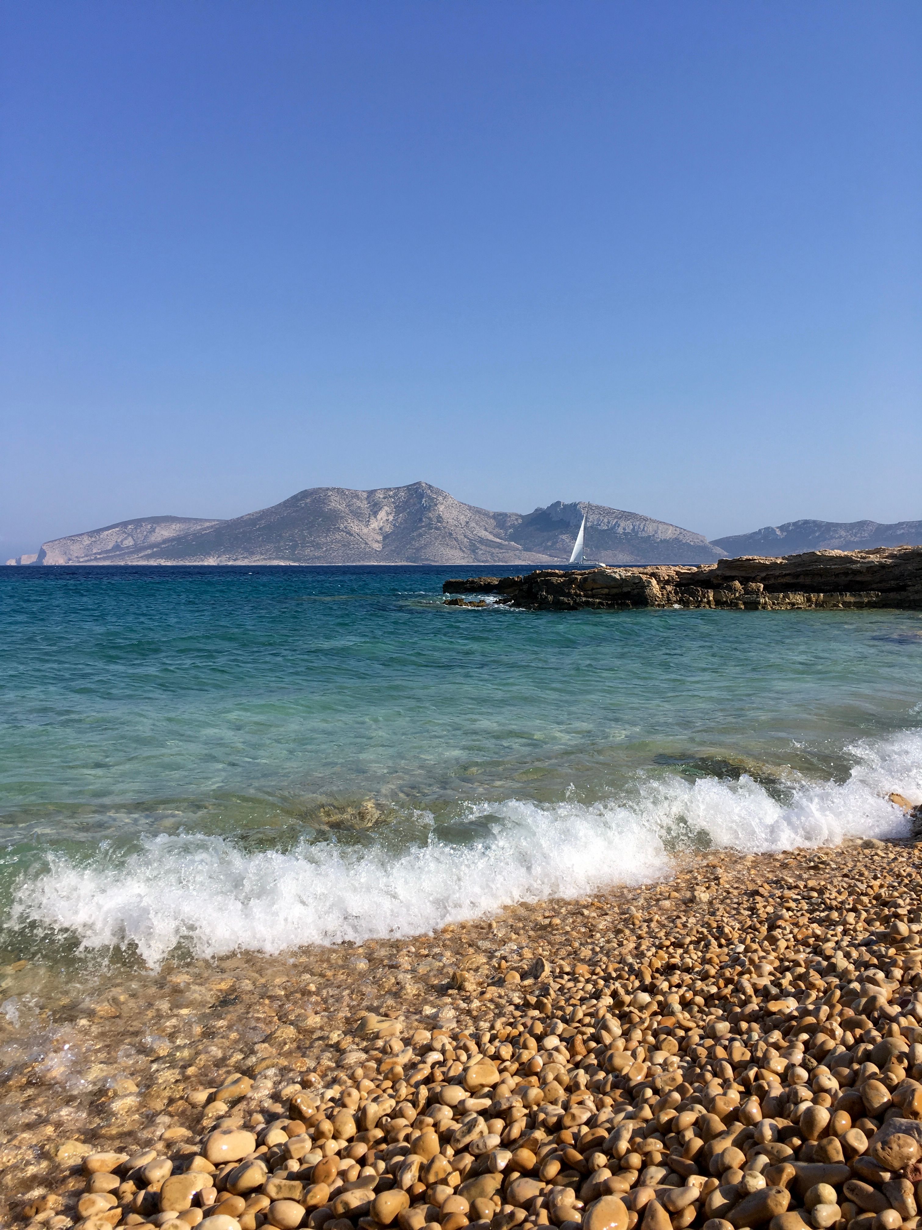 Serene pebble beach with view of Greek islands · Free Stock Photo