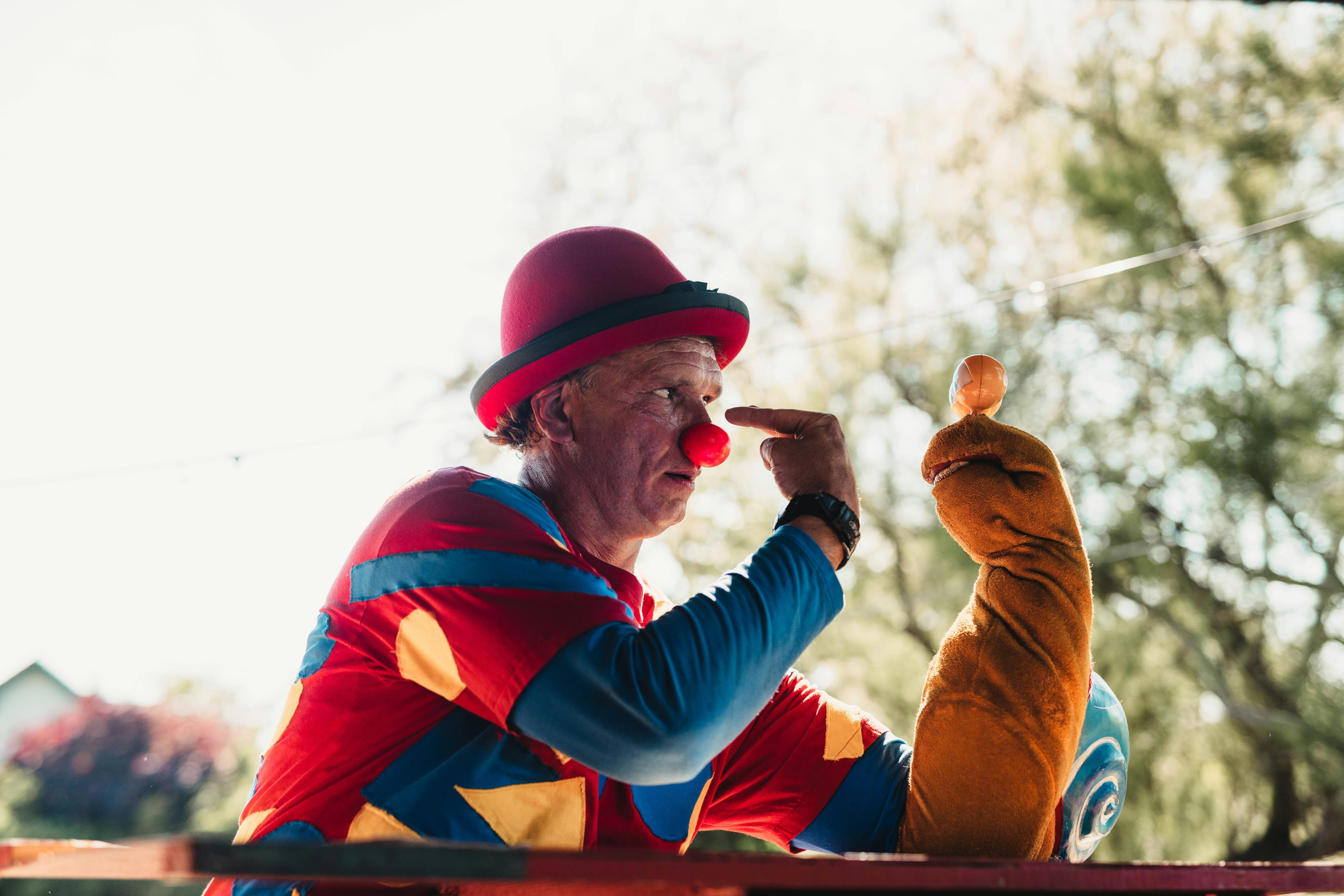 Colorful Clown Entertaining with Puppet Outdoors · Free Stock Photo