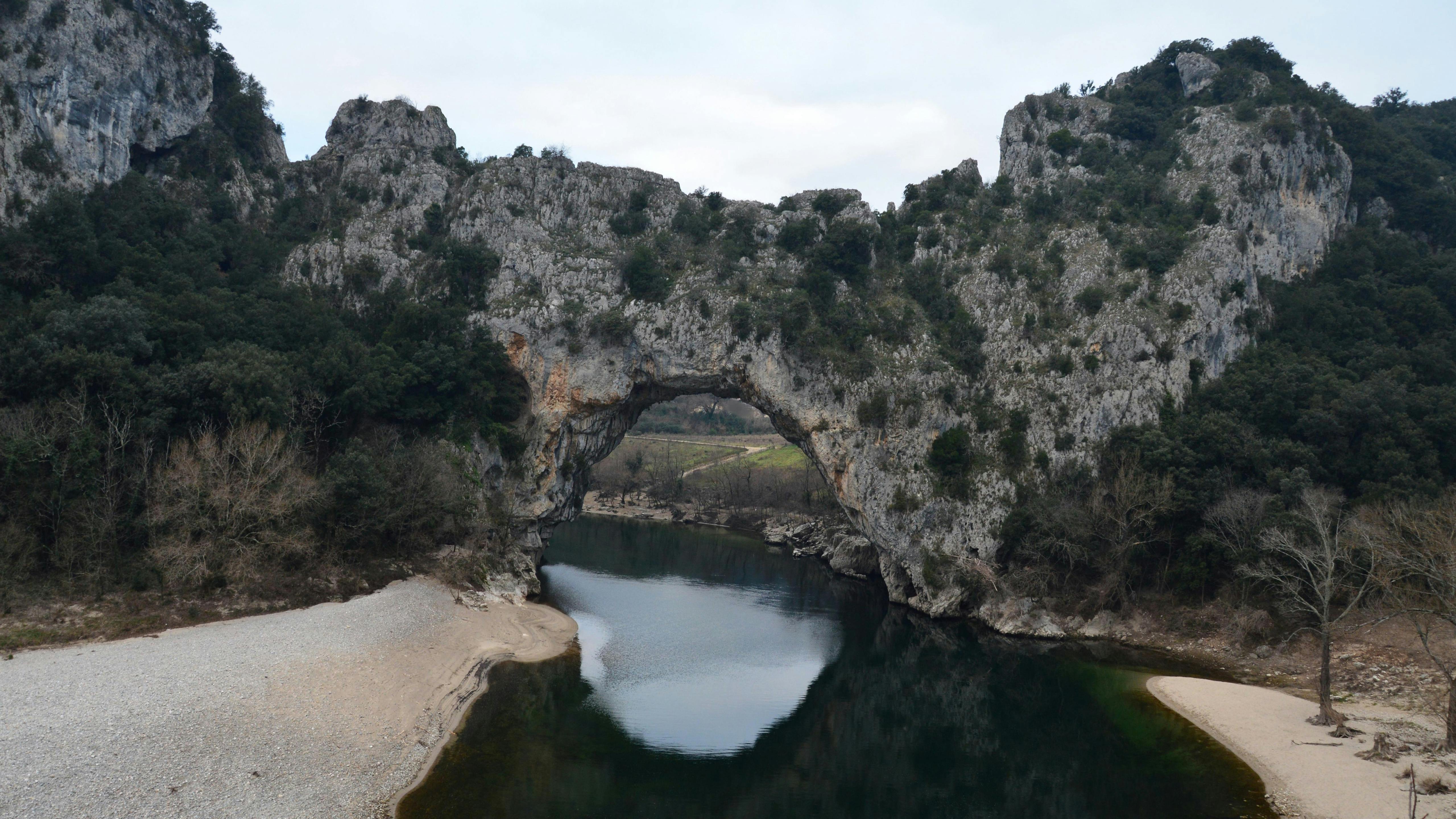 Natural Stone Arch Over Serene River Landscape · Free Stock Photo