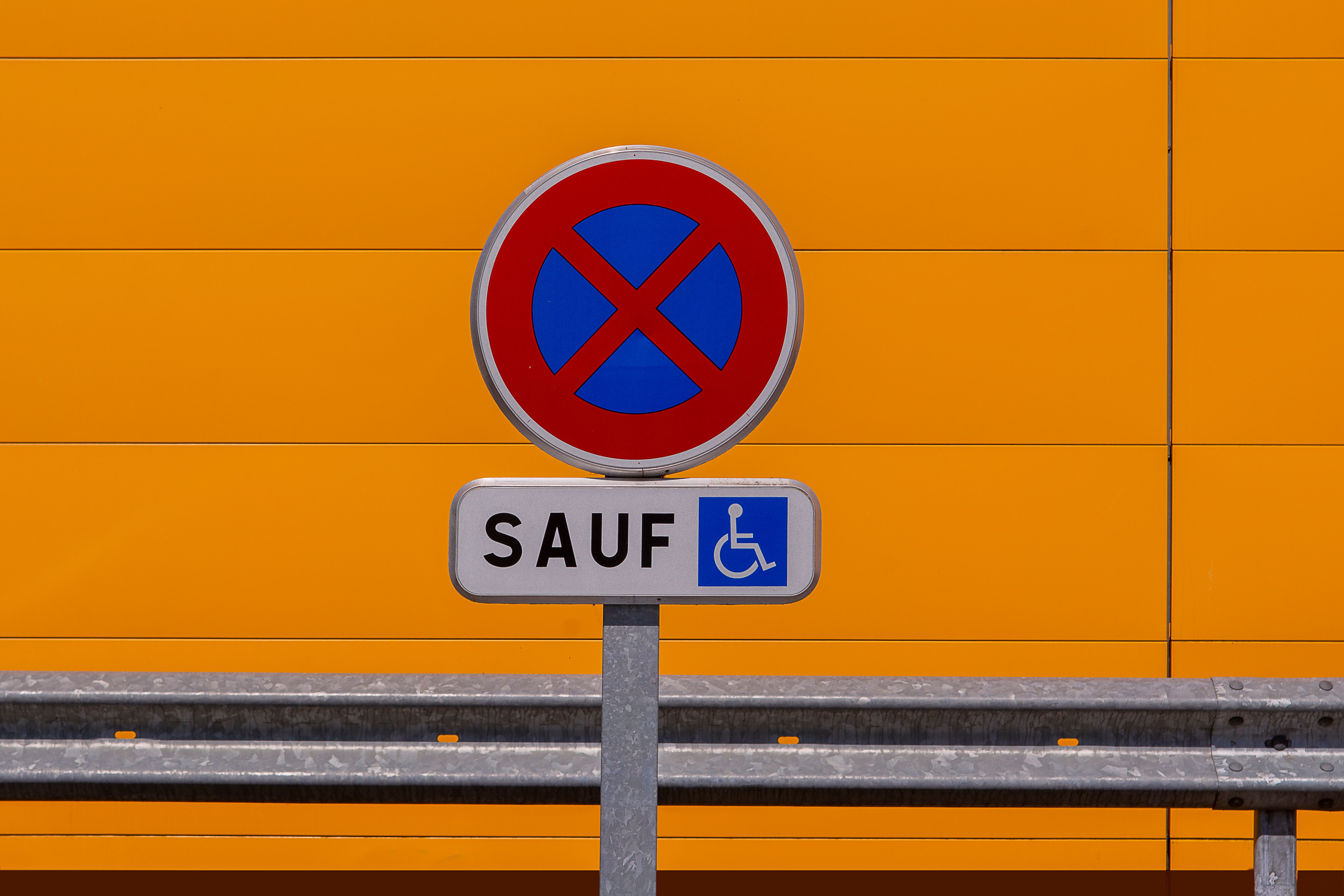 Disabled Parking Sign Against Orange Wall · Free Stock Photo