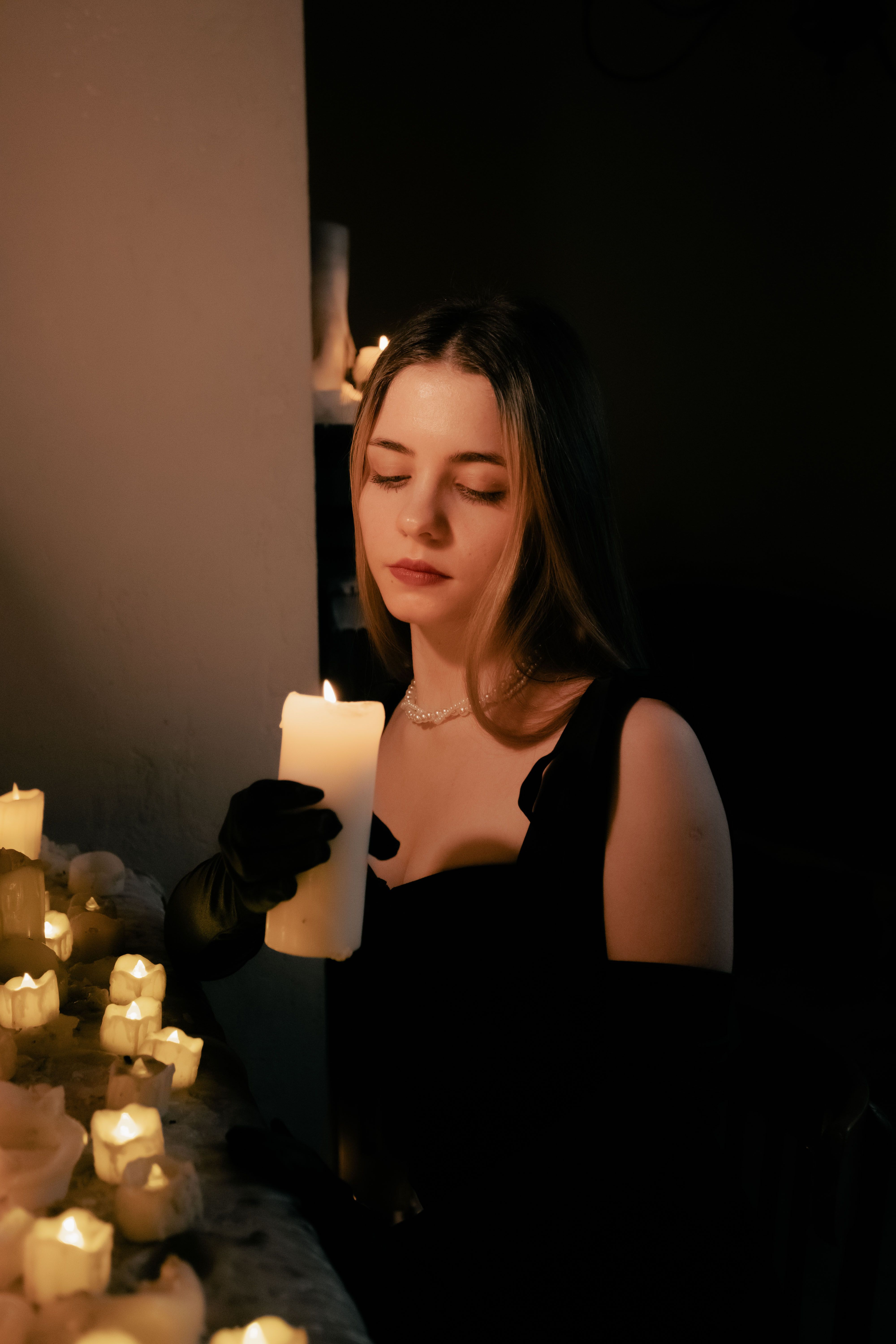 Contemplative Woman with Candle in Dim Light · Free Stock Photo