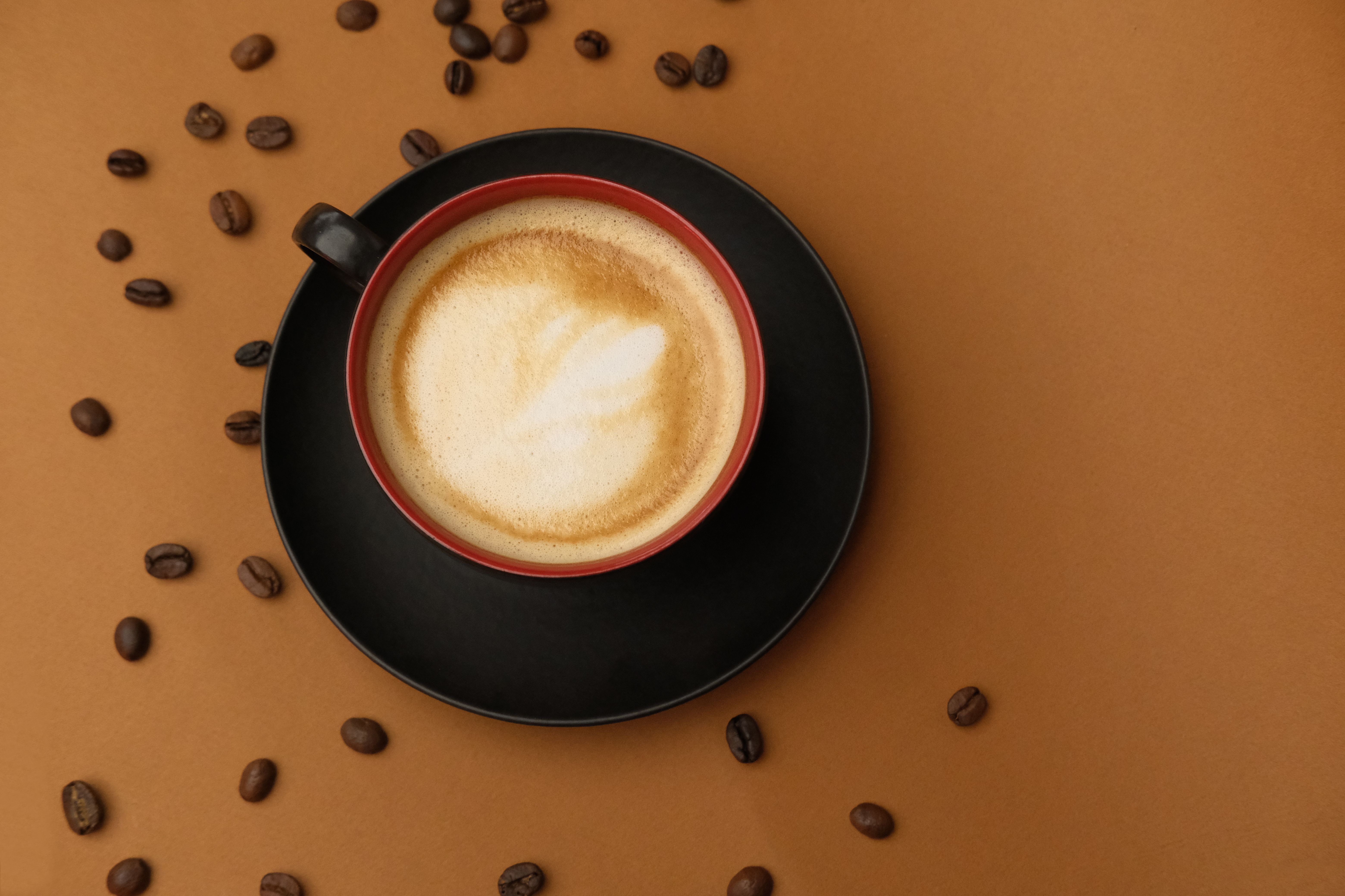 Elegant Coffee Cup with Frothy Art and Beans · Free Stock Photo