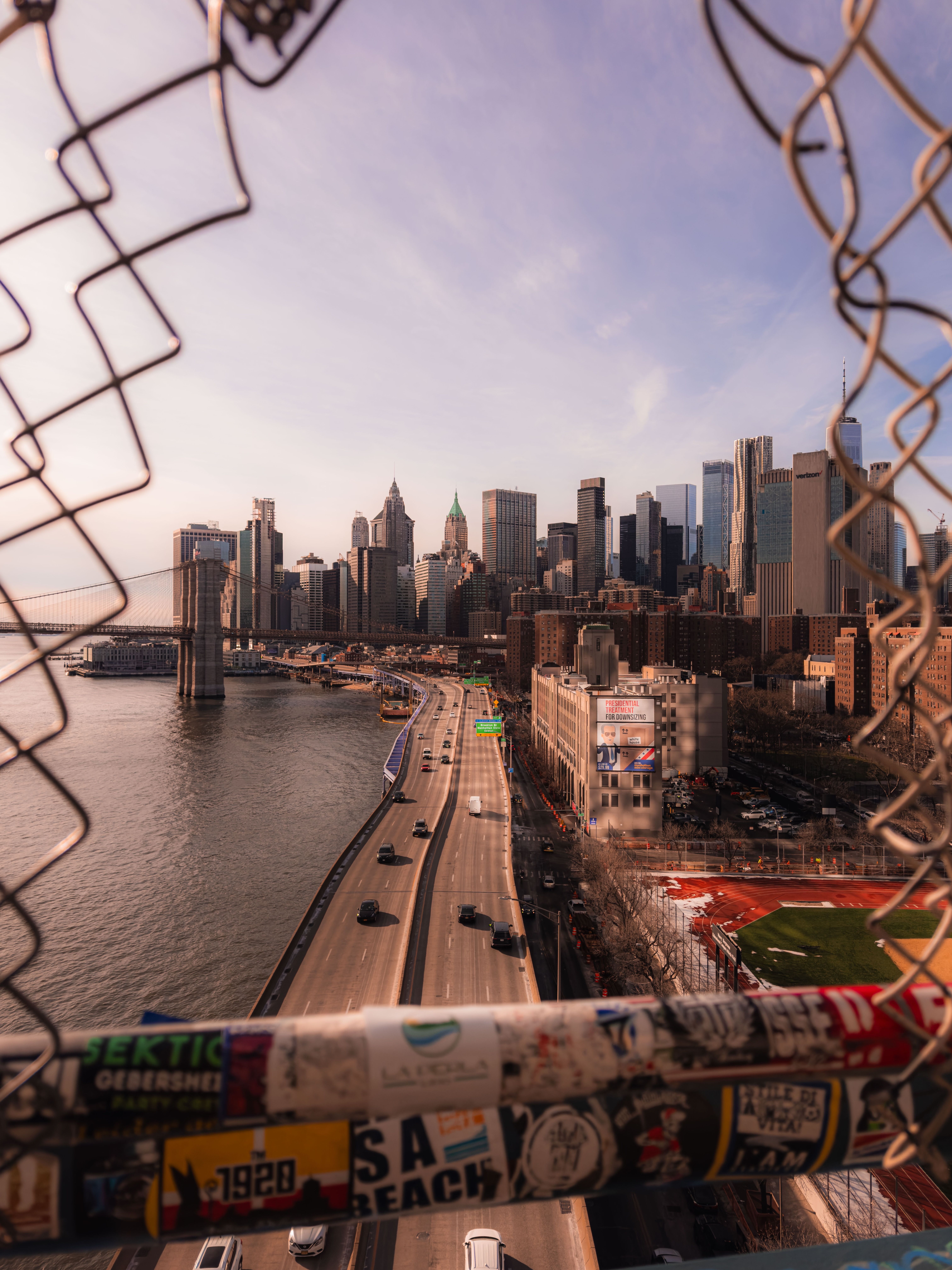 Cityscape of Manhattan Skyline through Chain Link Fence · Free Stock Photo