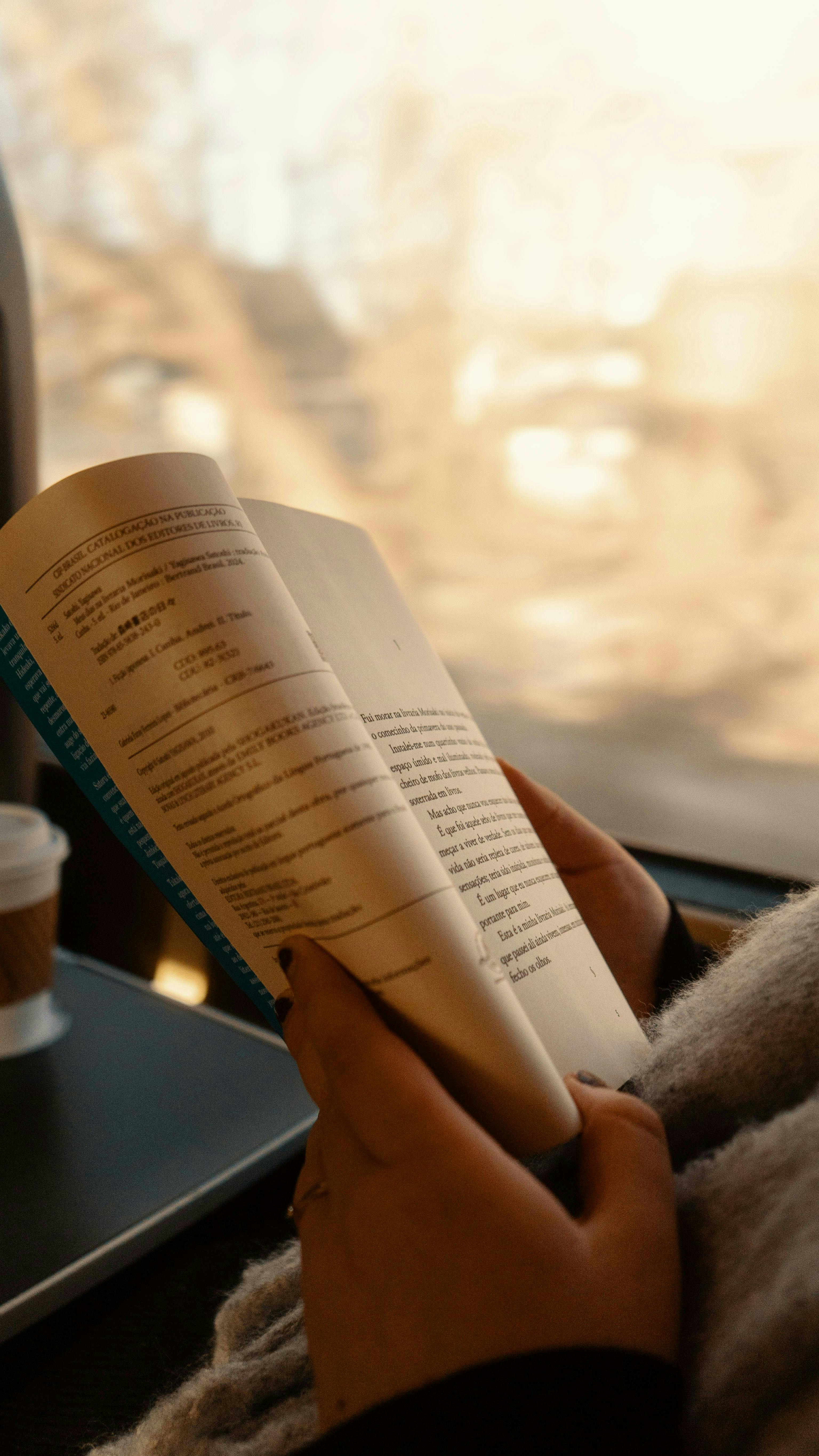 Person Reading on Train with Coffee · Free Stock Photo