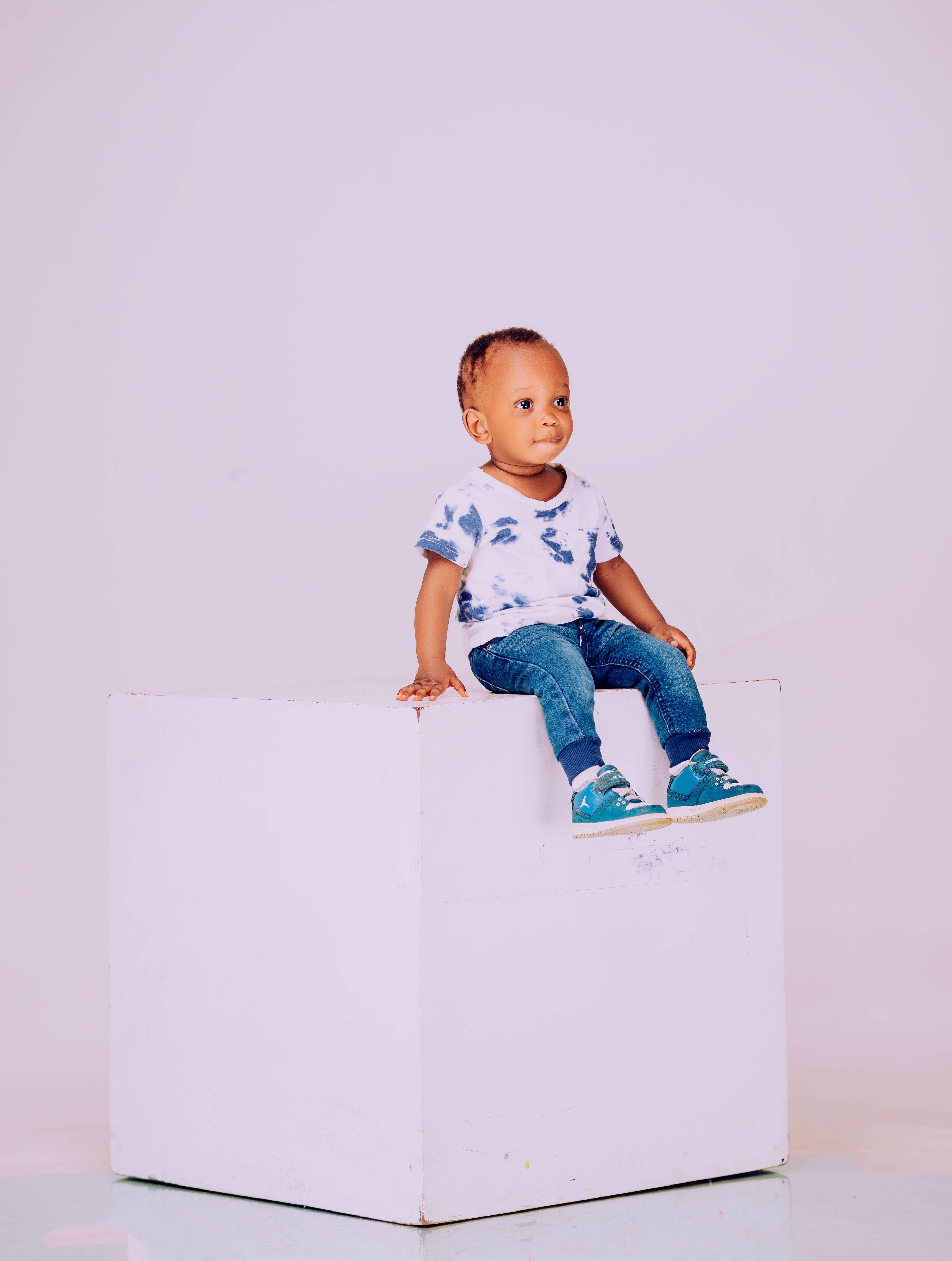 Adorable Child Sitting on White Cube in Studio · Free Stock Photo