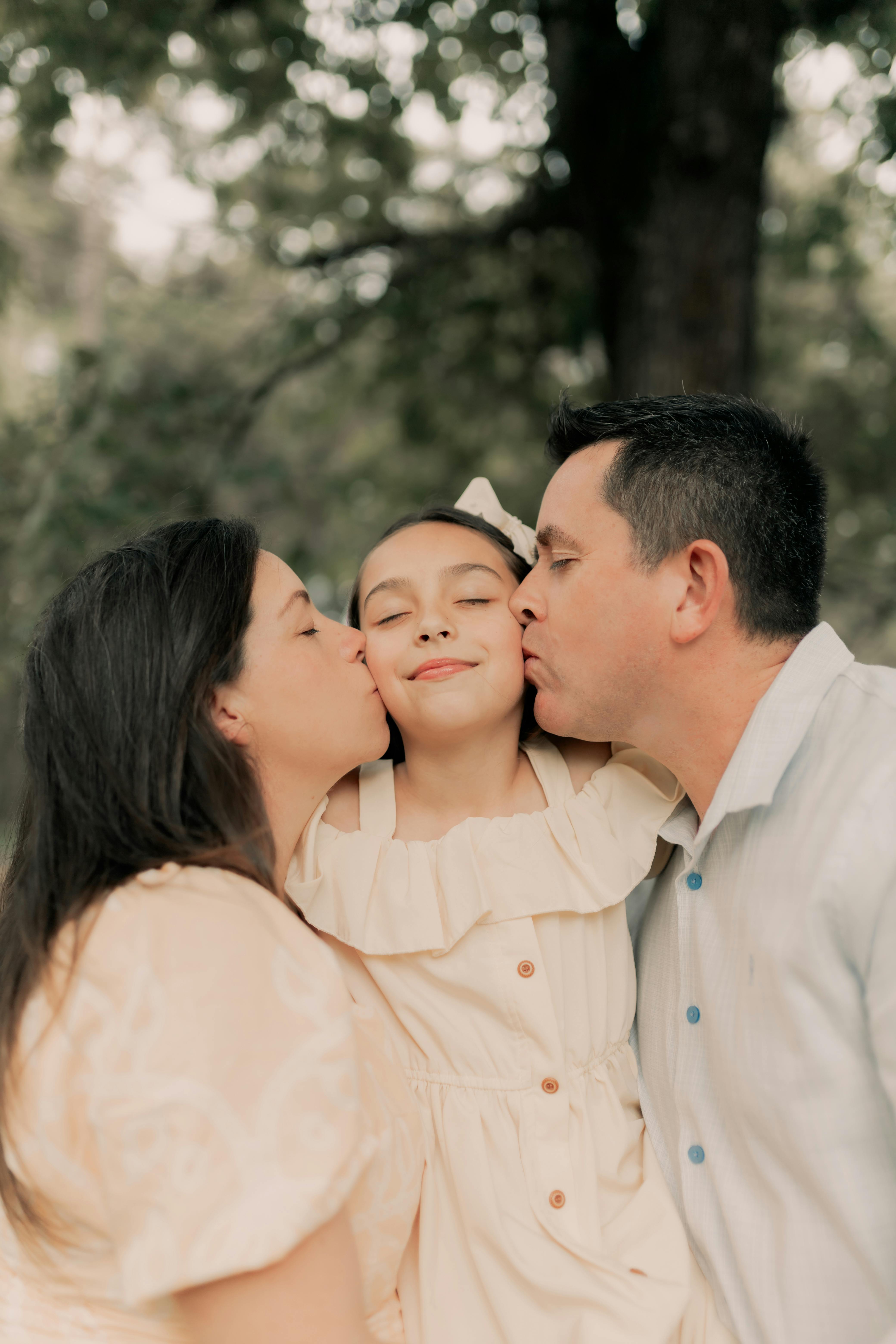 Family Affection Outdoors: Parents Kissing Child · Free Stock Photo