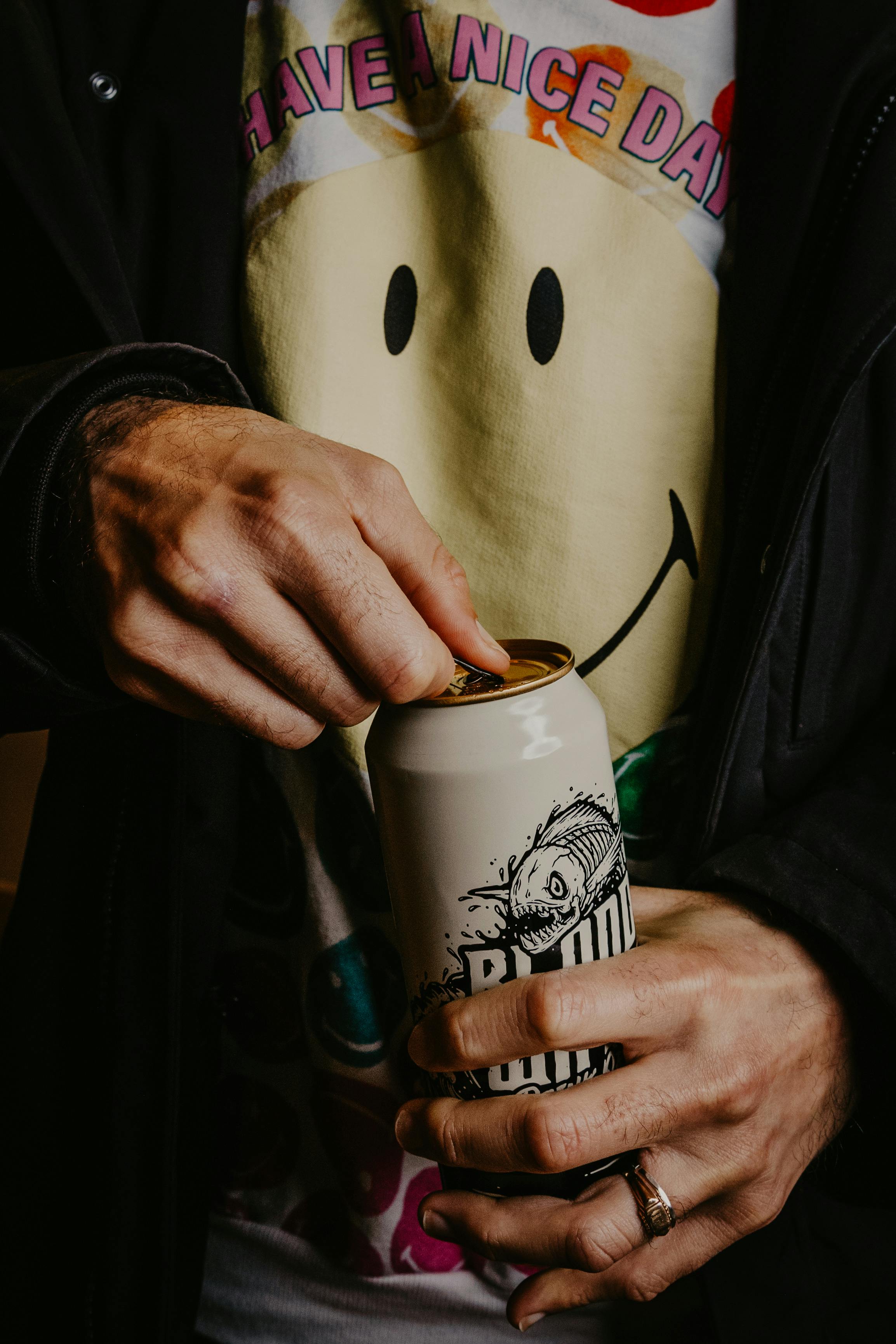 Person Opening Can with Smiley Face Shirt · Free Stock Photo