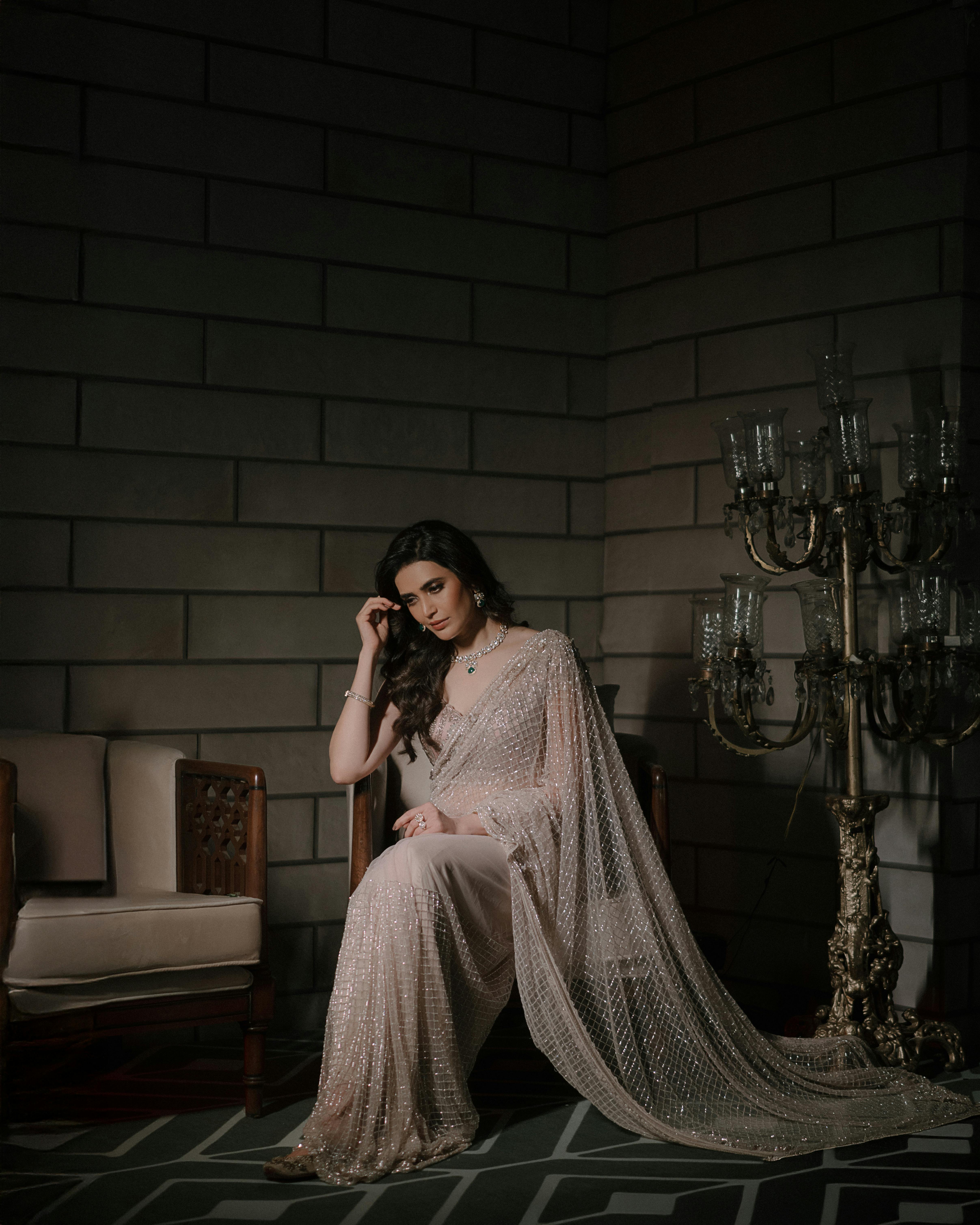 Elegant Woman in Shimmering Saree Sitting Indoors · Free Stock Photo