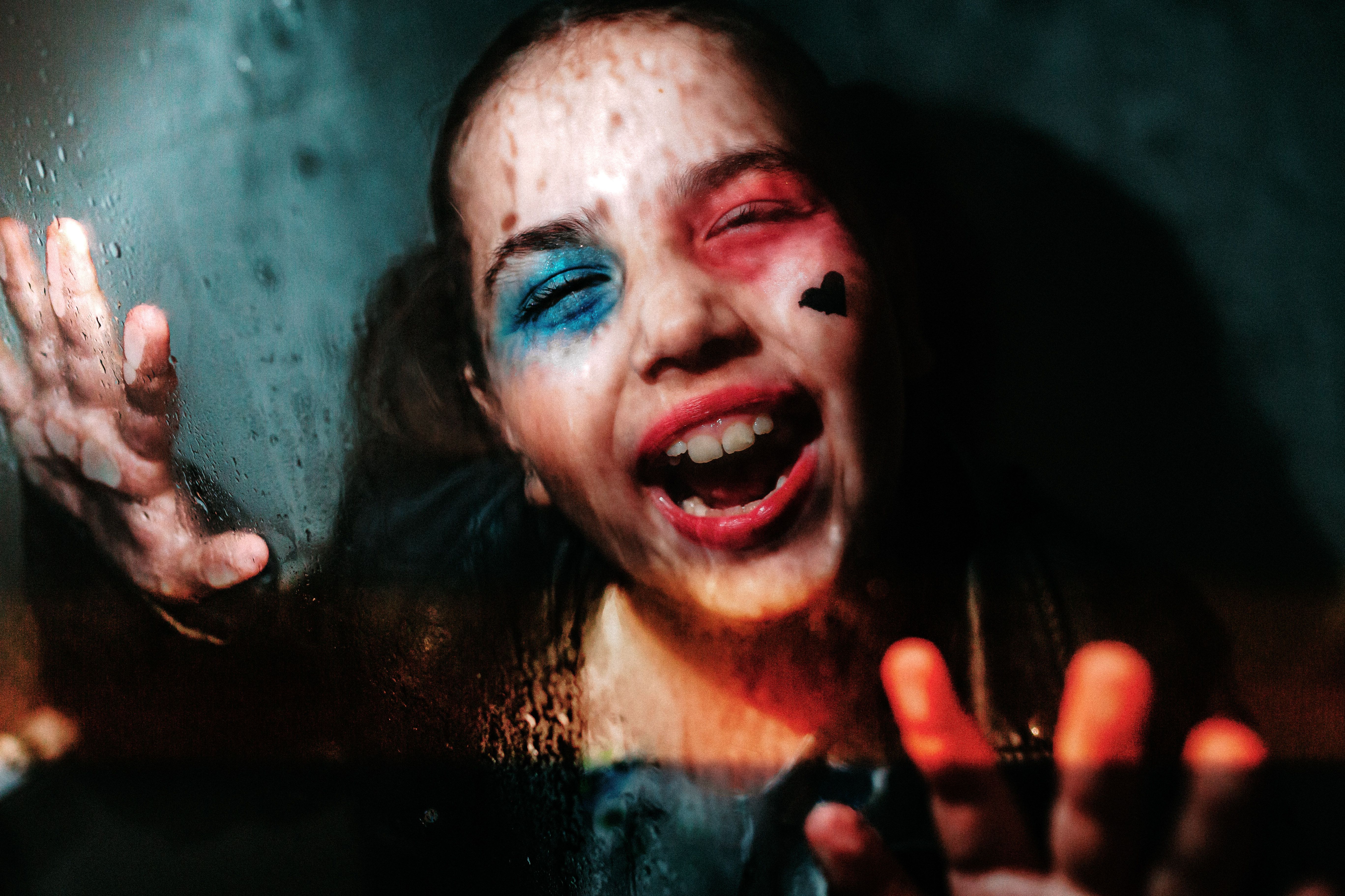Joyful Child with Painted Face Behind Wet Glass · Free Stock Photo