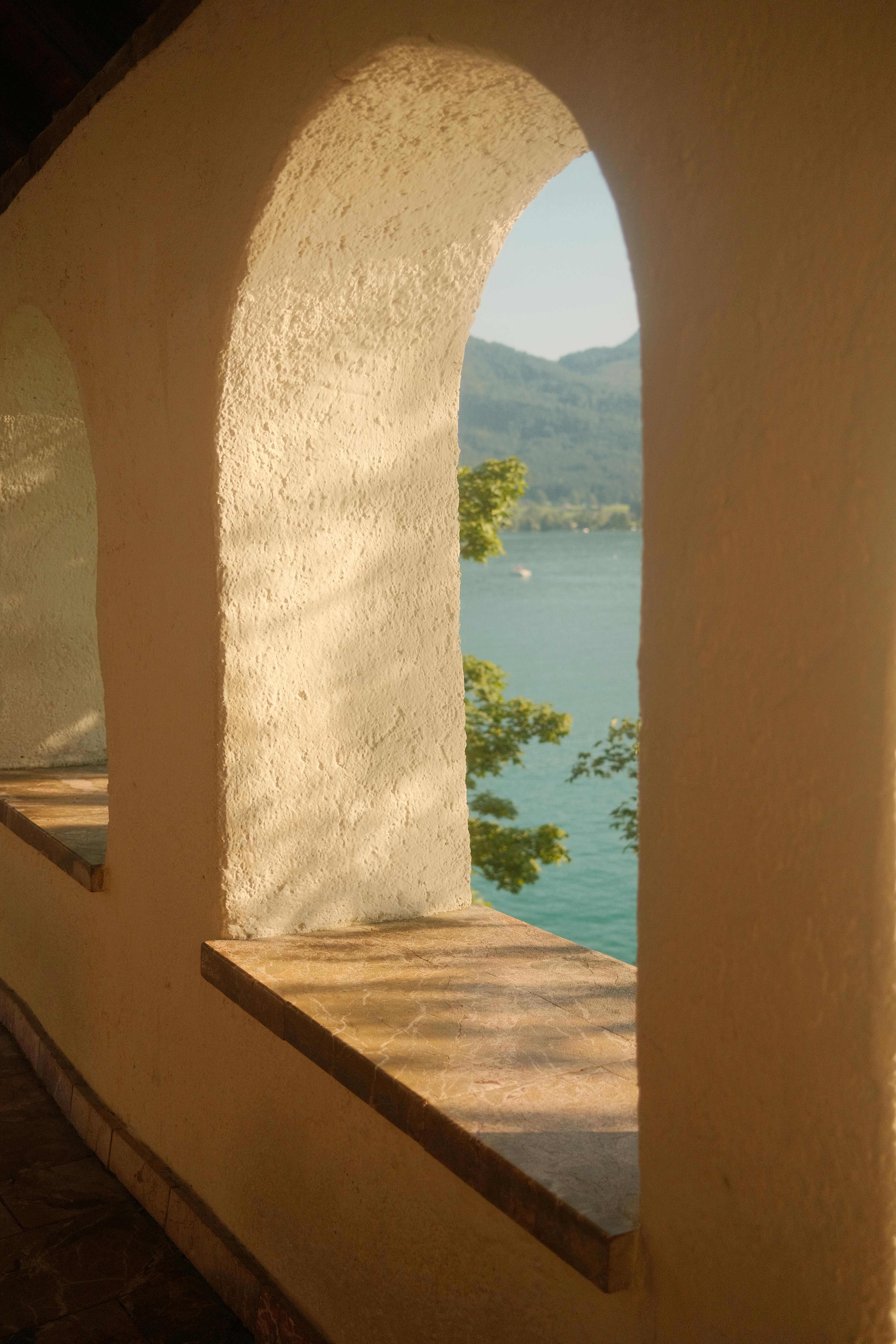 Serene Lake View Through Rustic Arch Windows · Free Stock Photo