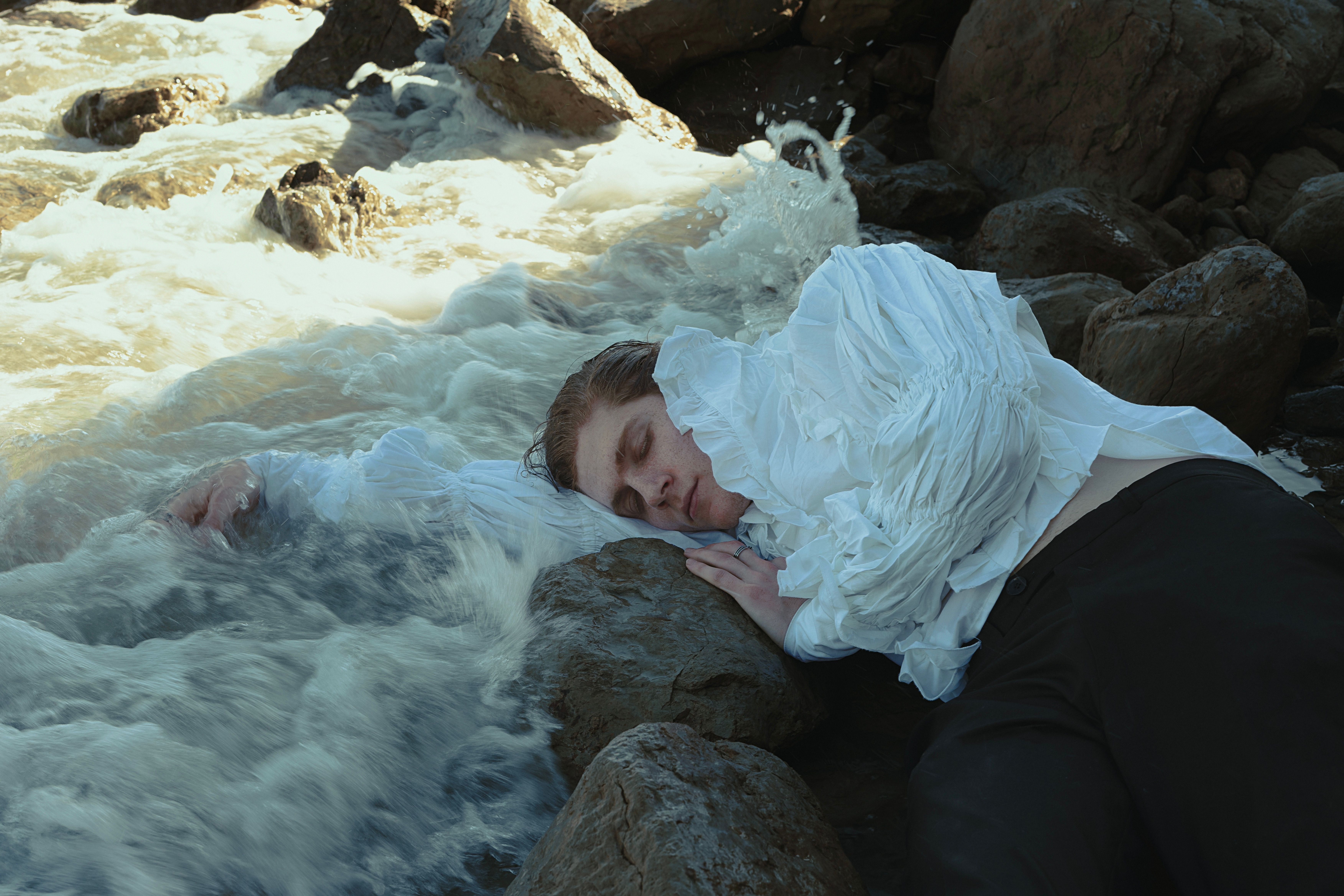 Dramatic Portrait in Flowing Water on Rocky Shore · Free Stock Photo