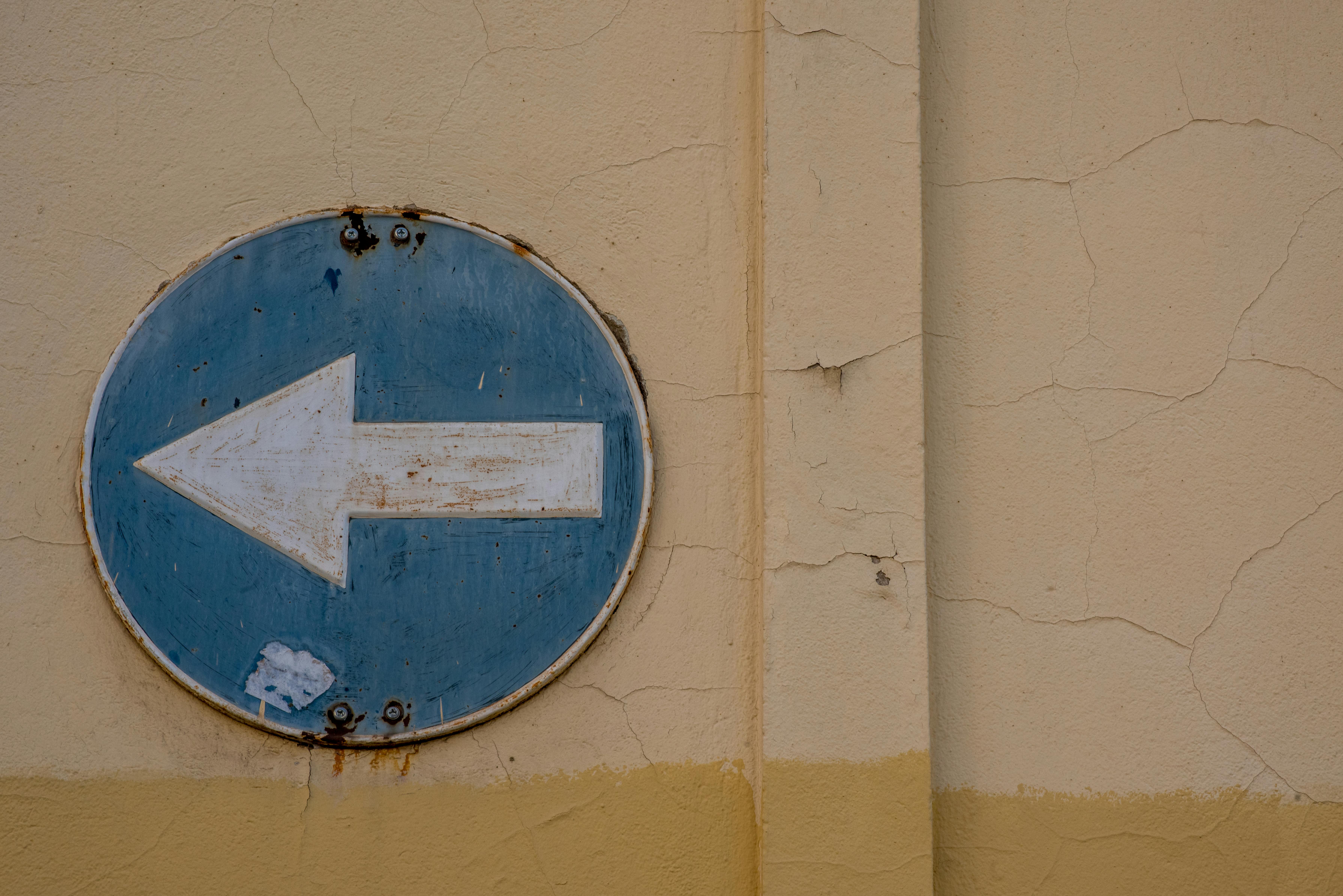 Old Blue Left Arrow Traffic Sign on Cracked Wall · Free Stock Photo