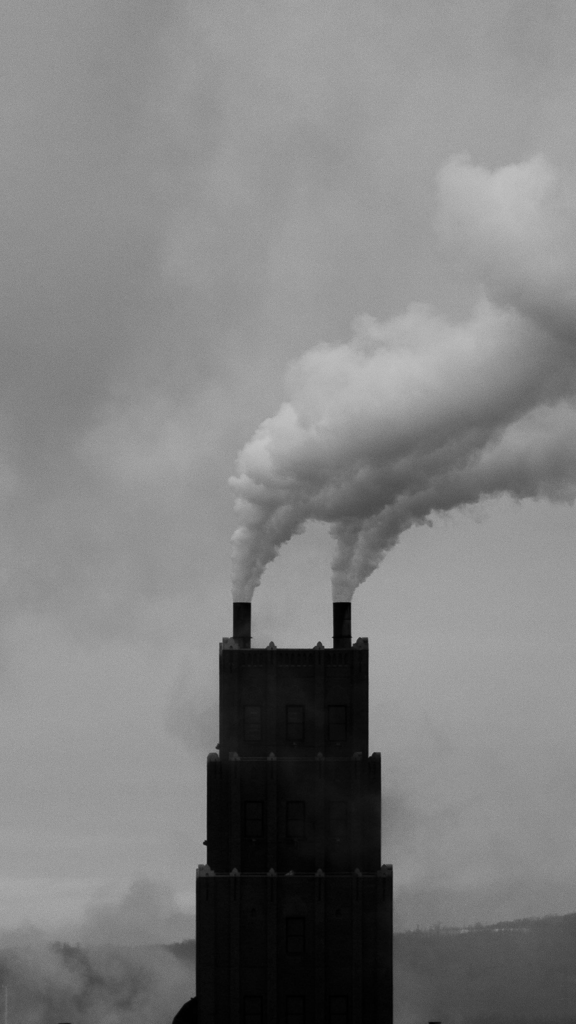 Industrial smokestack emitting pollution in grayscale · Free Stock Photo