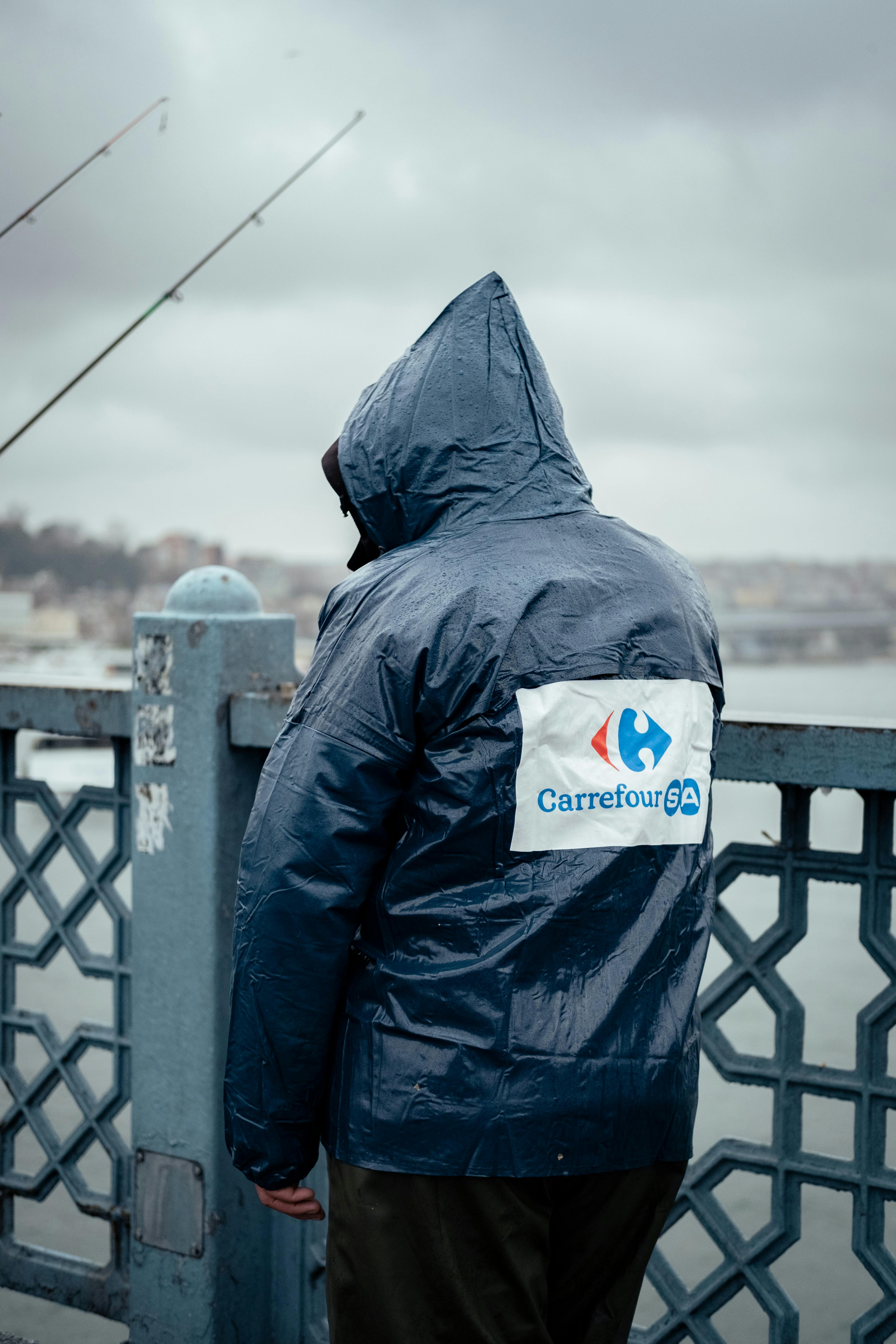 Person in Raincoat Facing River on Overcast Day · Free Stock Photo