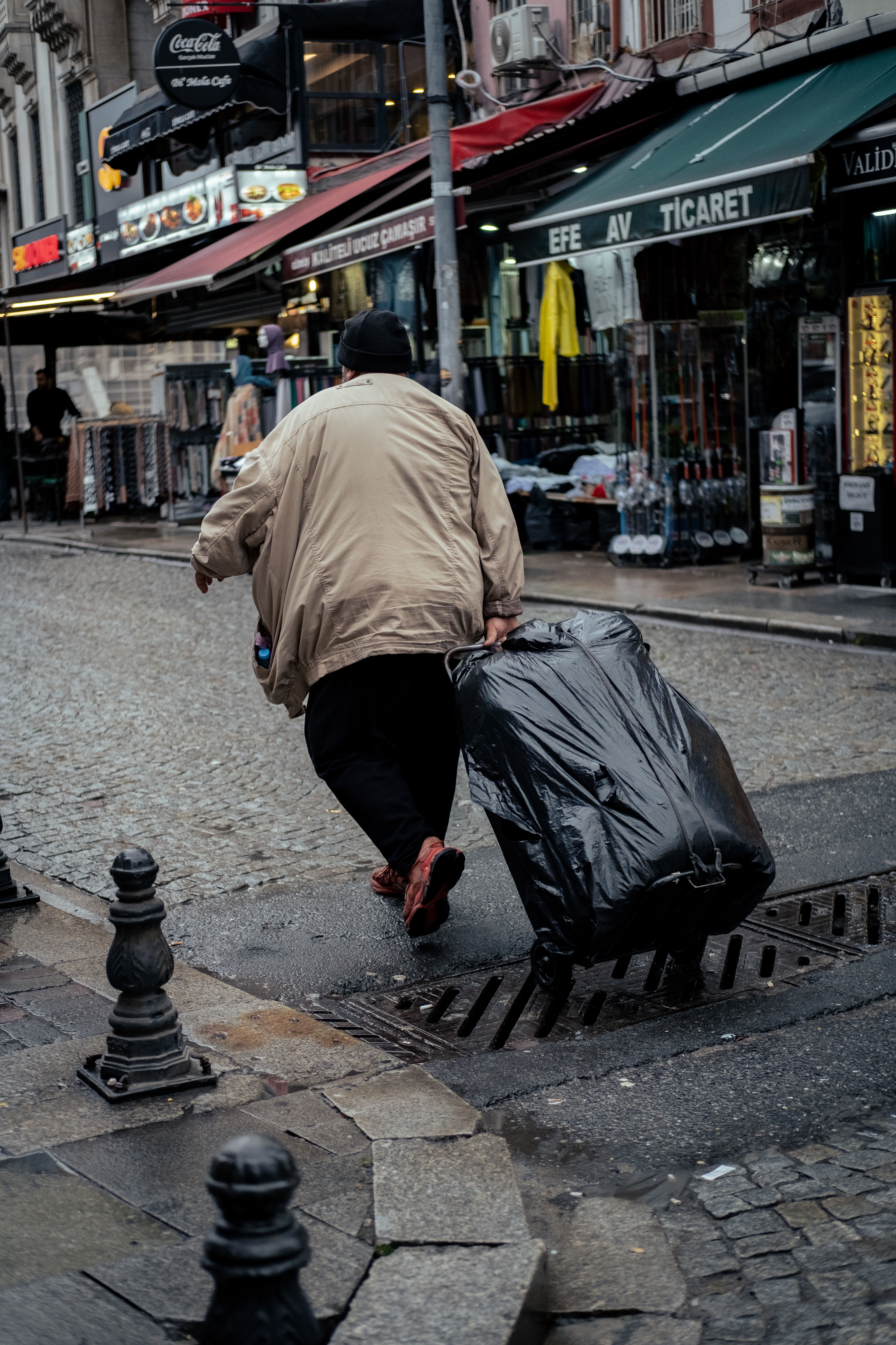 Urban Street Scene with Man Pulling Trash Bag · Free Stock Photo