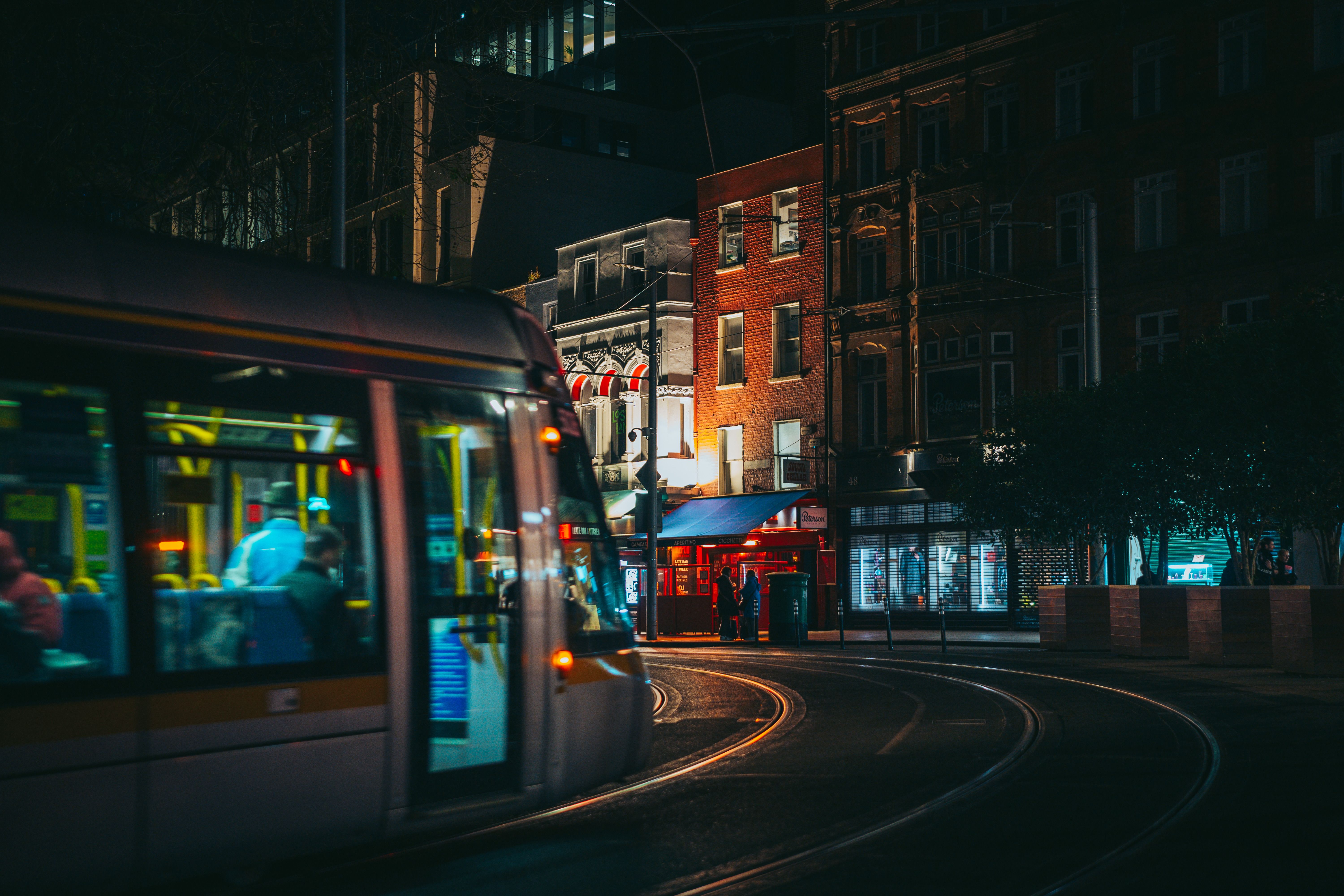 Night Street Scene with Moving Tram and Shops · Free Stock Photo