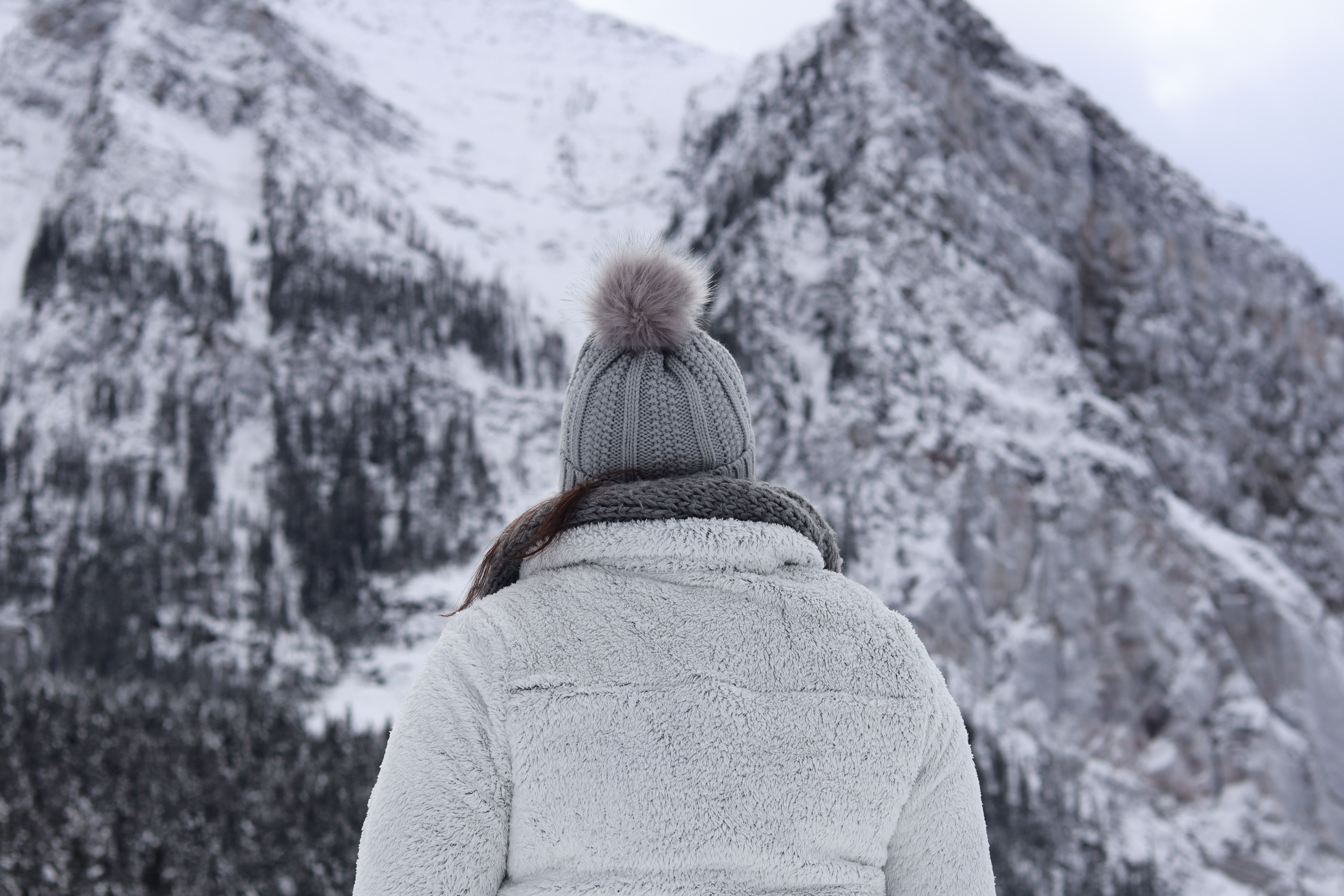 Woman in Winter Coat Facing Snowy Mountains · Free Stock Photo