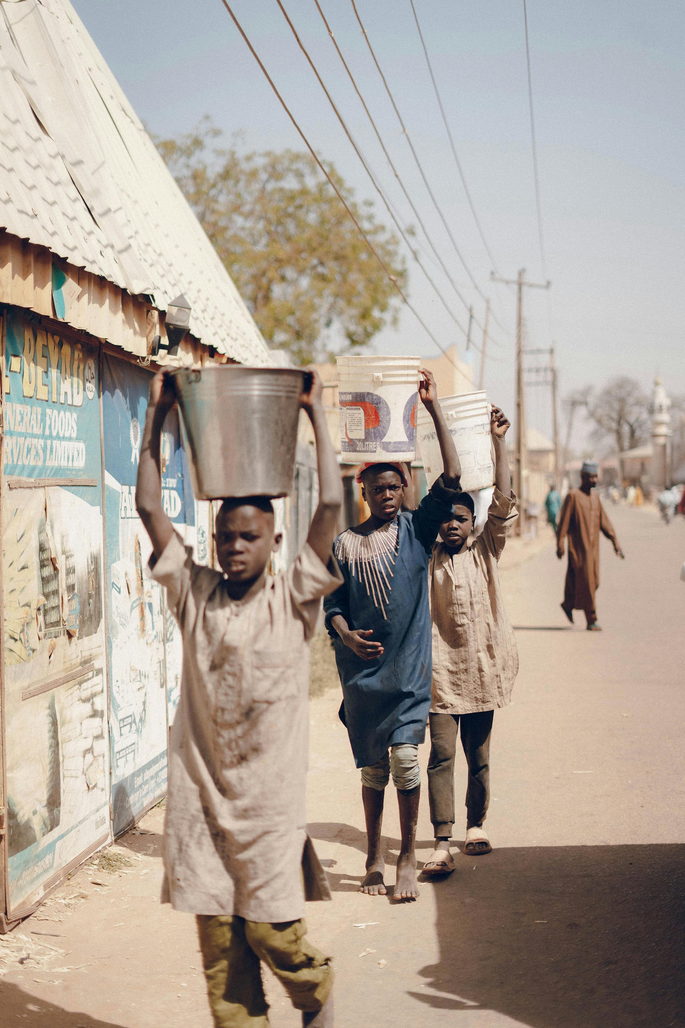 Young Boys Carrying Water Buckets on Street · Free Stock Photo