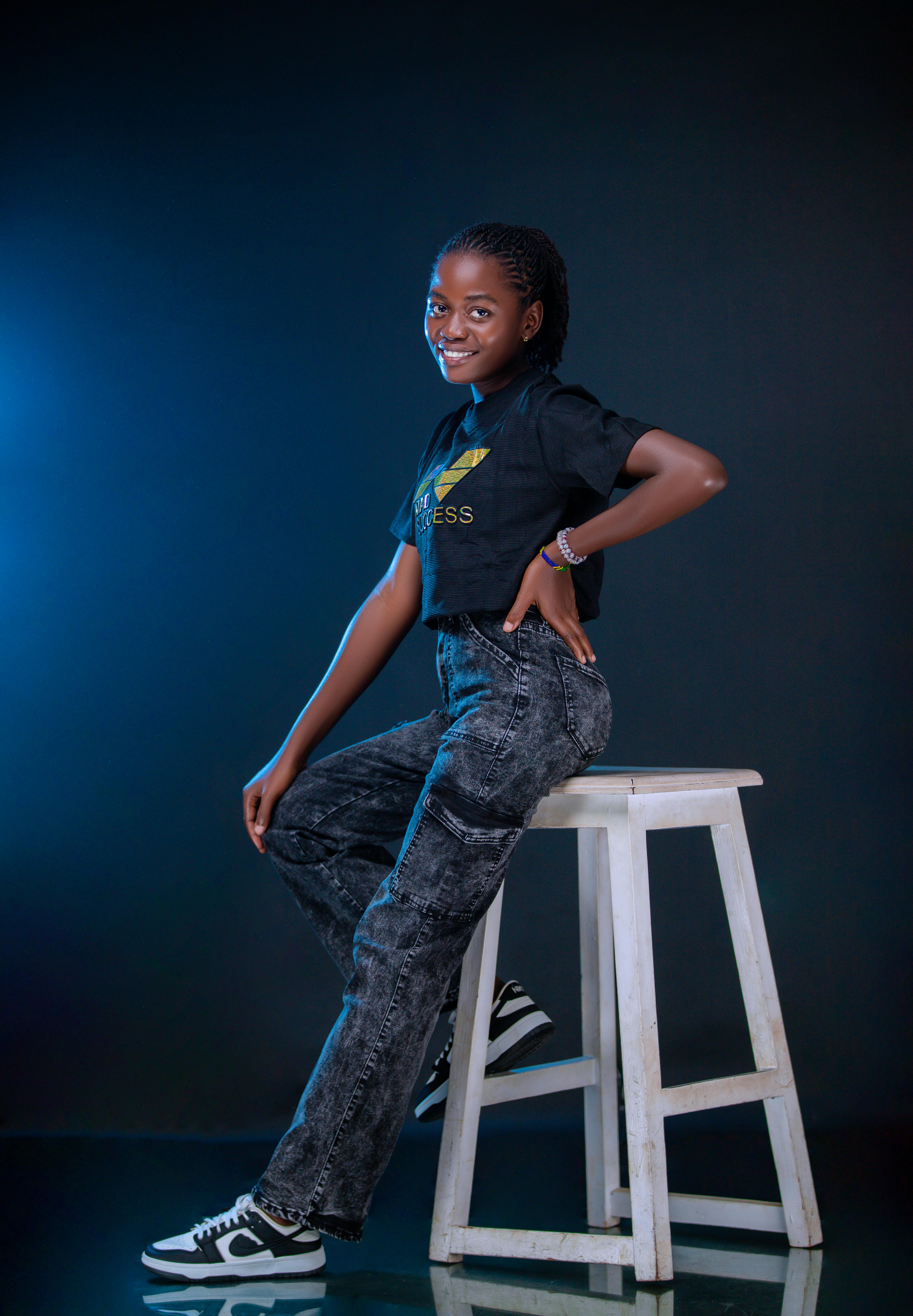 Fashionable Teen Smiling on Stool in Studio · Free Stock Photo