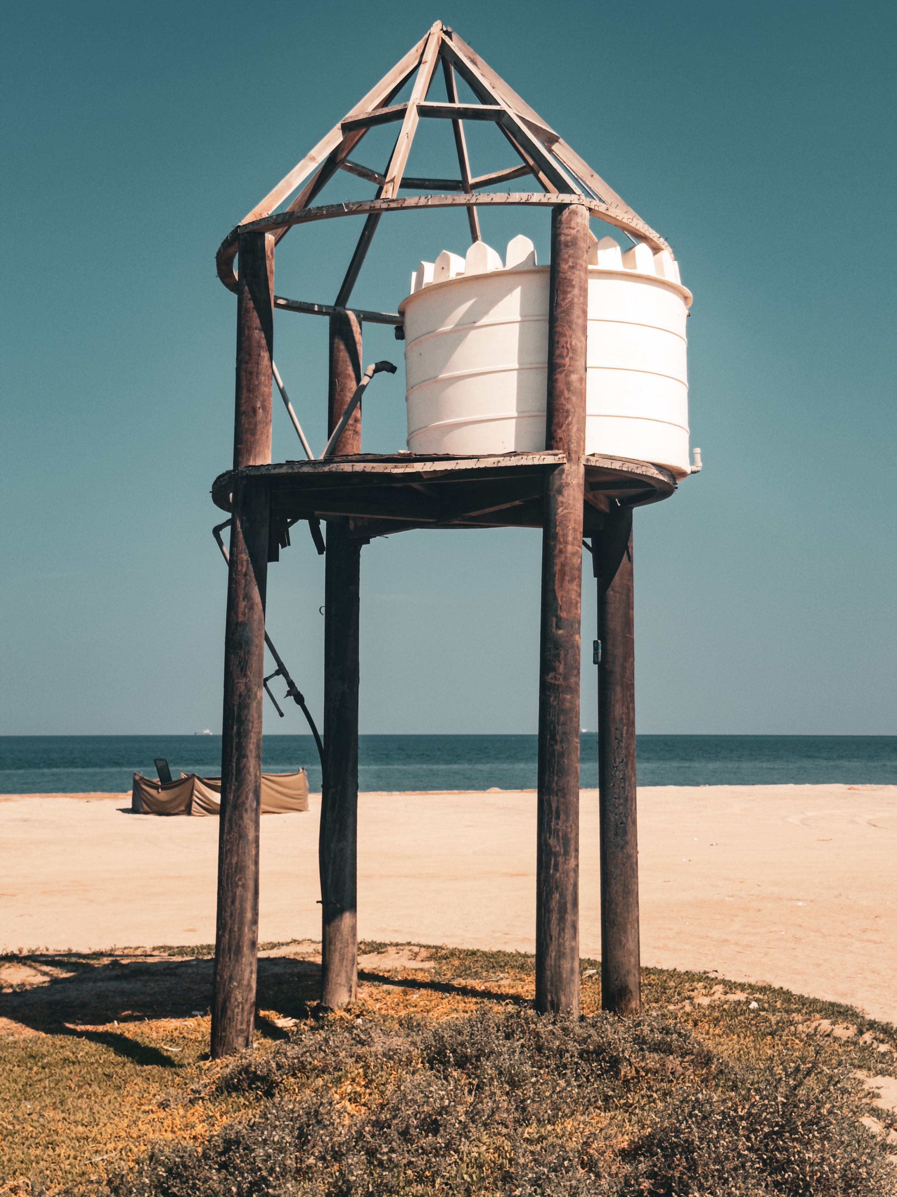 Wooden Structure with Water Tank on a Sandy Beach · Free Stock Photo