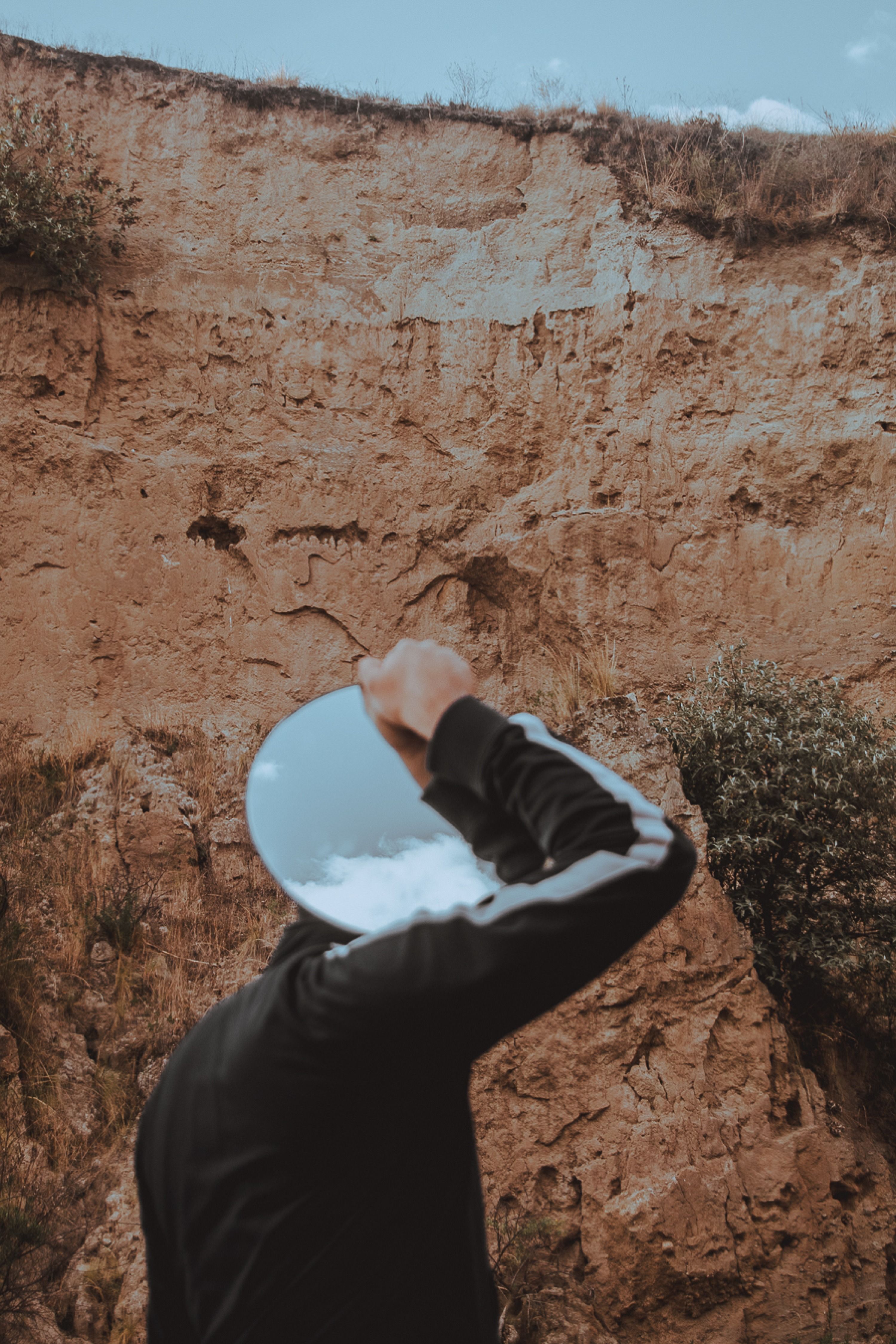Man Holding Mirror Against Rocky Cliff · Free Stock Photo