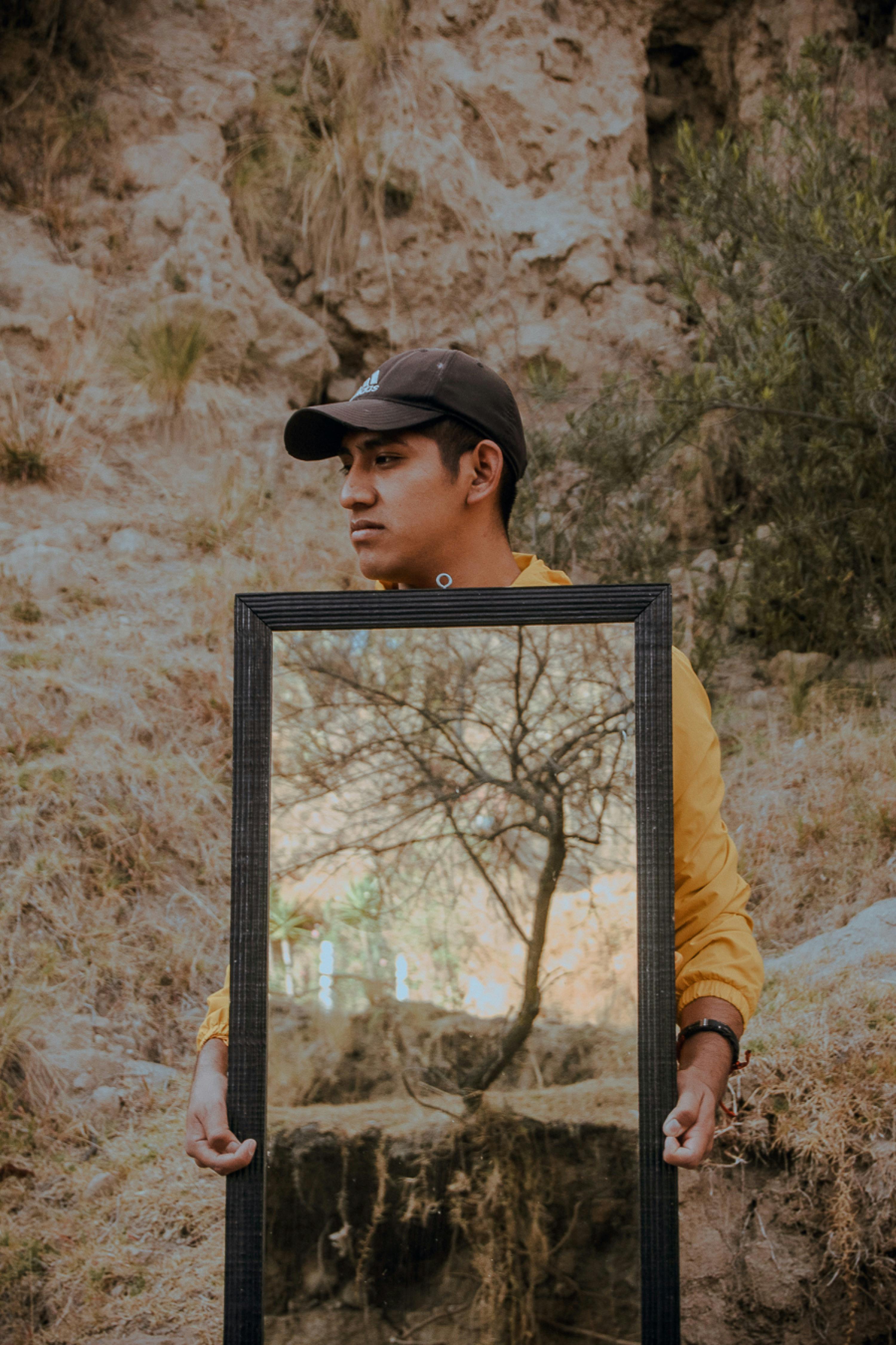 Man Holding Mirror Reflecting Tree Outdoors · Free Stock Photo