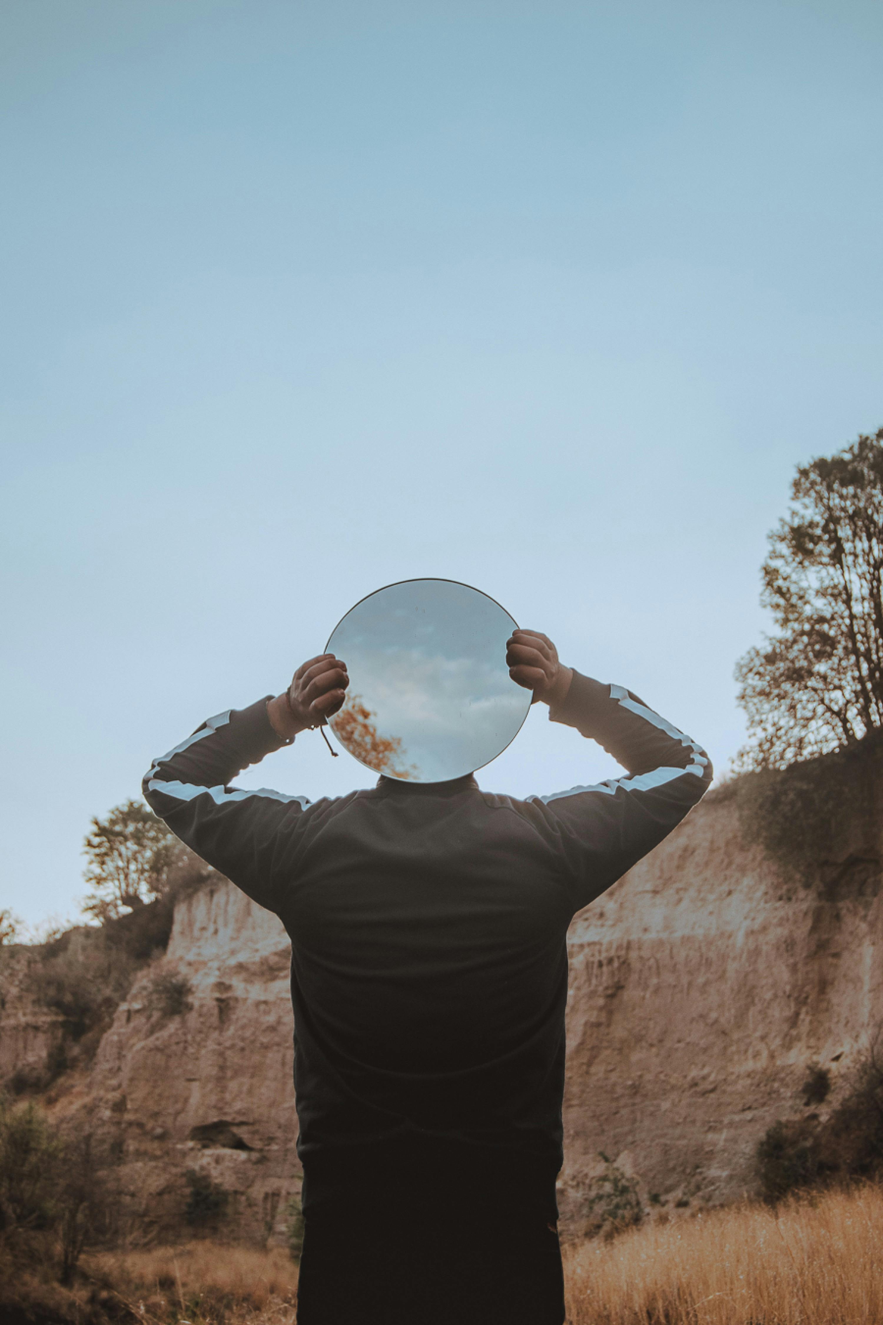 Man Holding Mirror Reflecting Sky Outdoors · Free Stock Photo